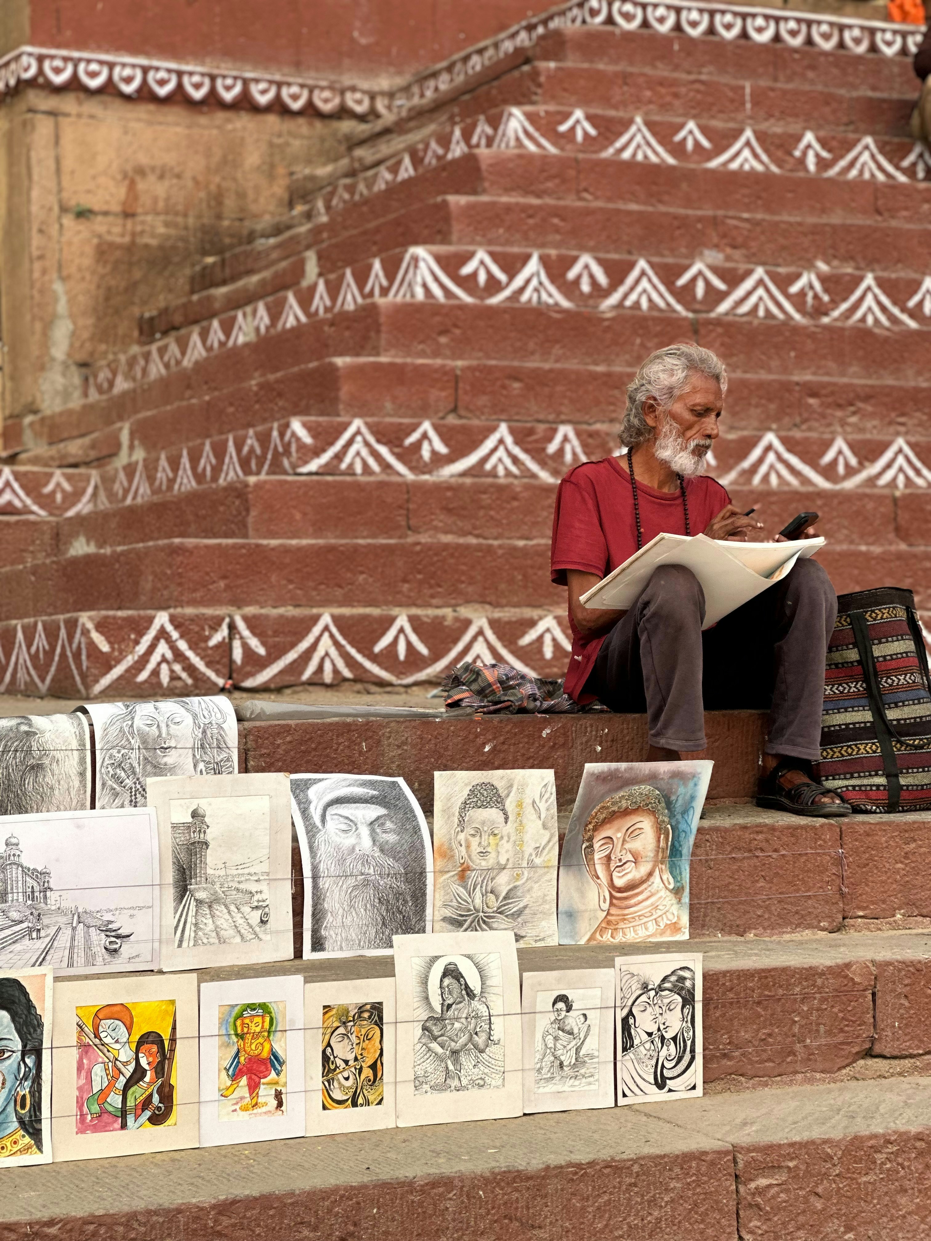 Sketches on the Steps: A Street Artist Sits Amid Colorful Prints