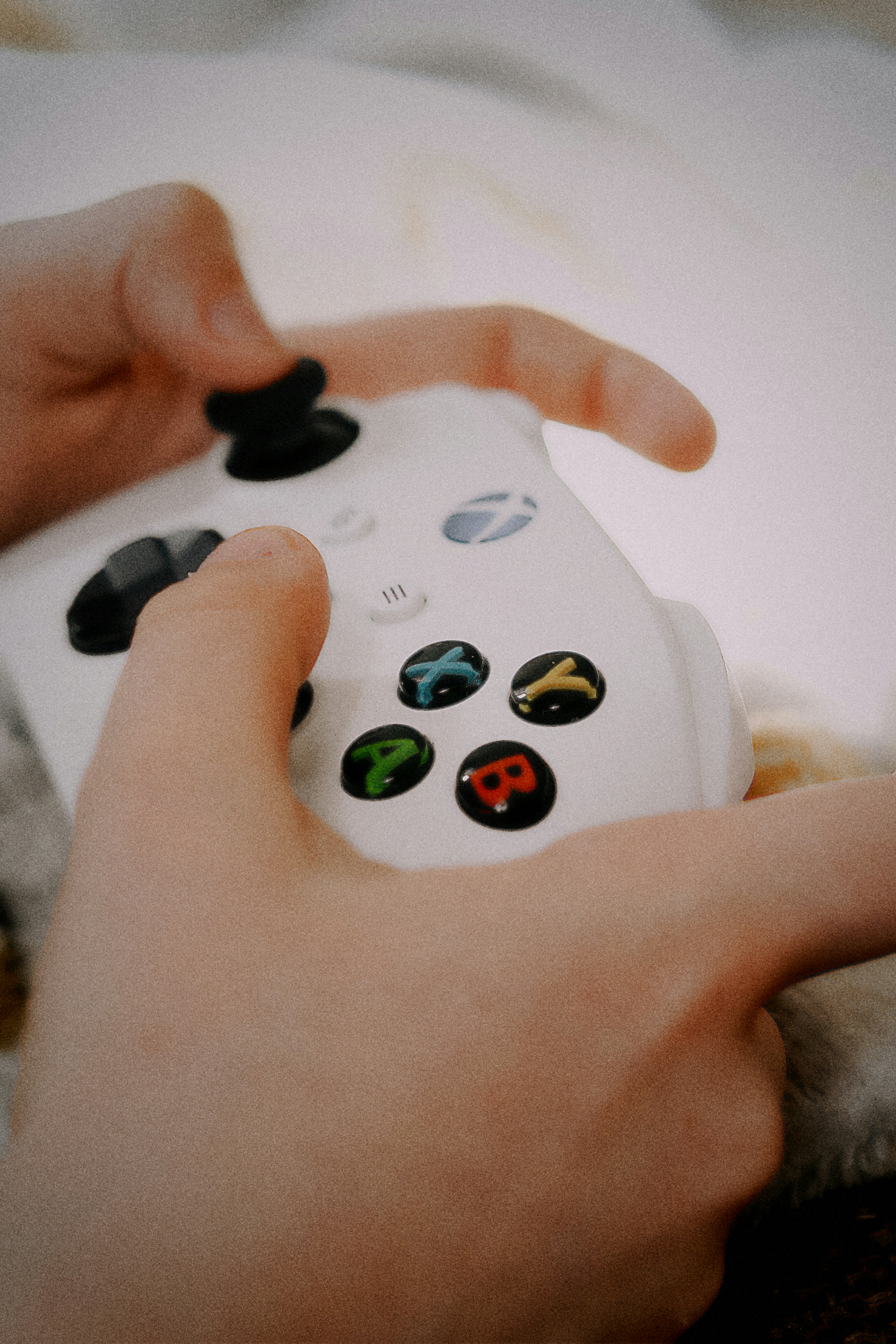 Close-Play: Fingers Grip the White Controller as Colors Pop on Game Buttons