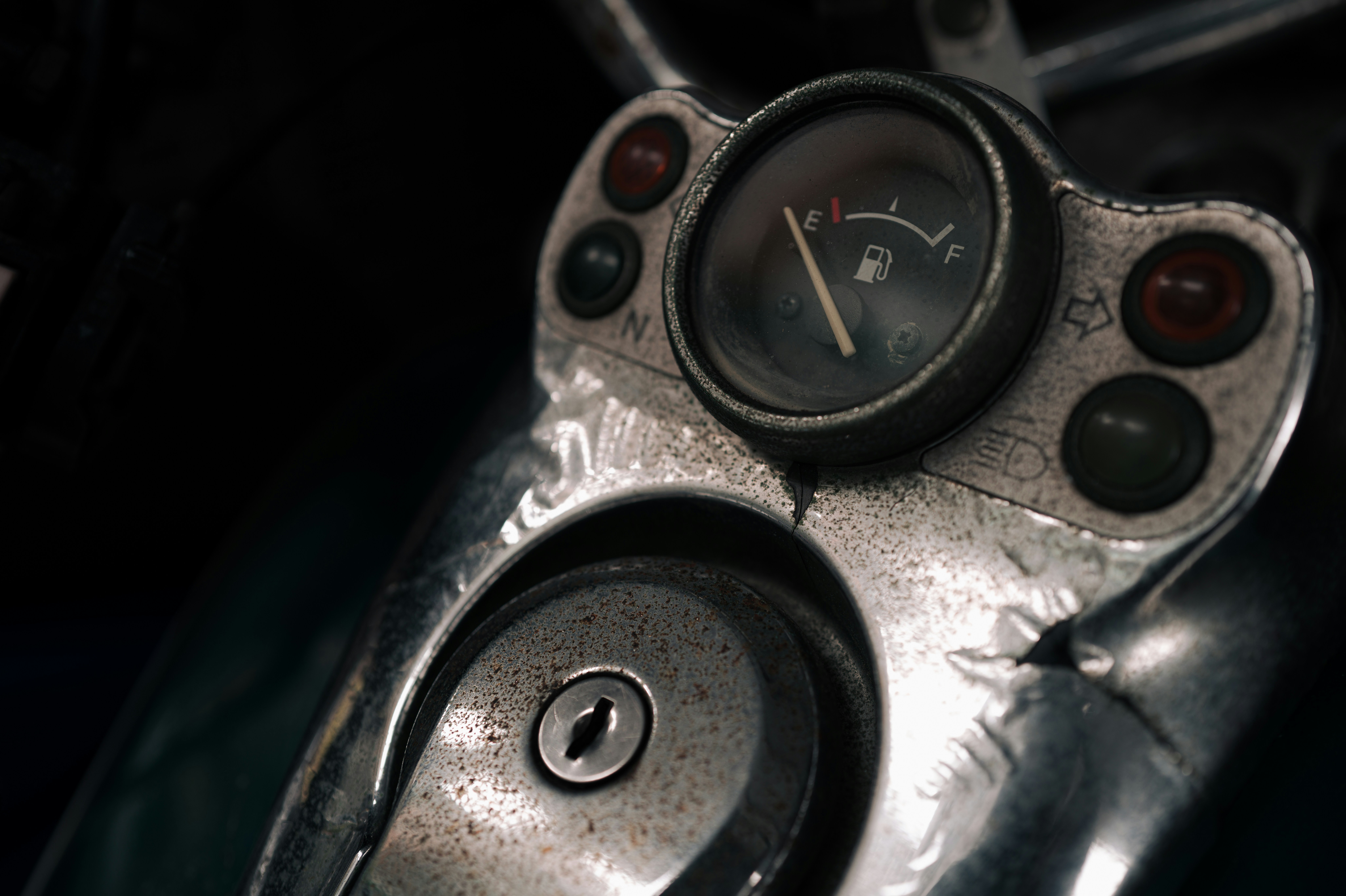 Weathered motorcycle console: a close-up of a dusty gauge and ignition ring