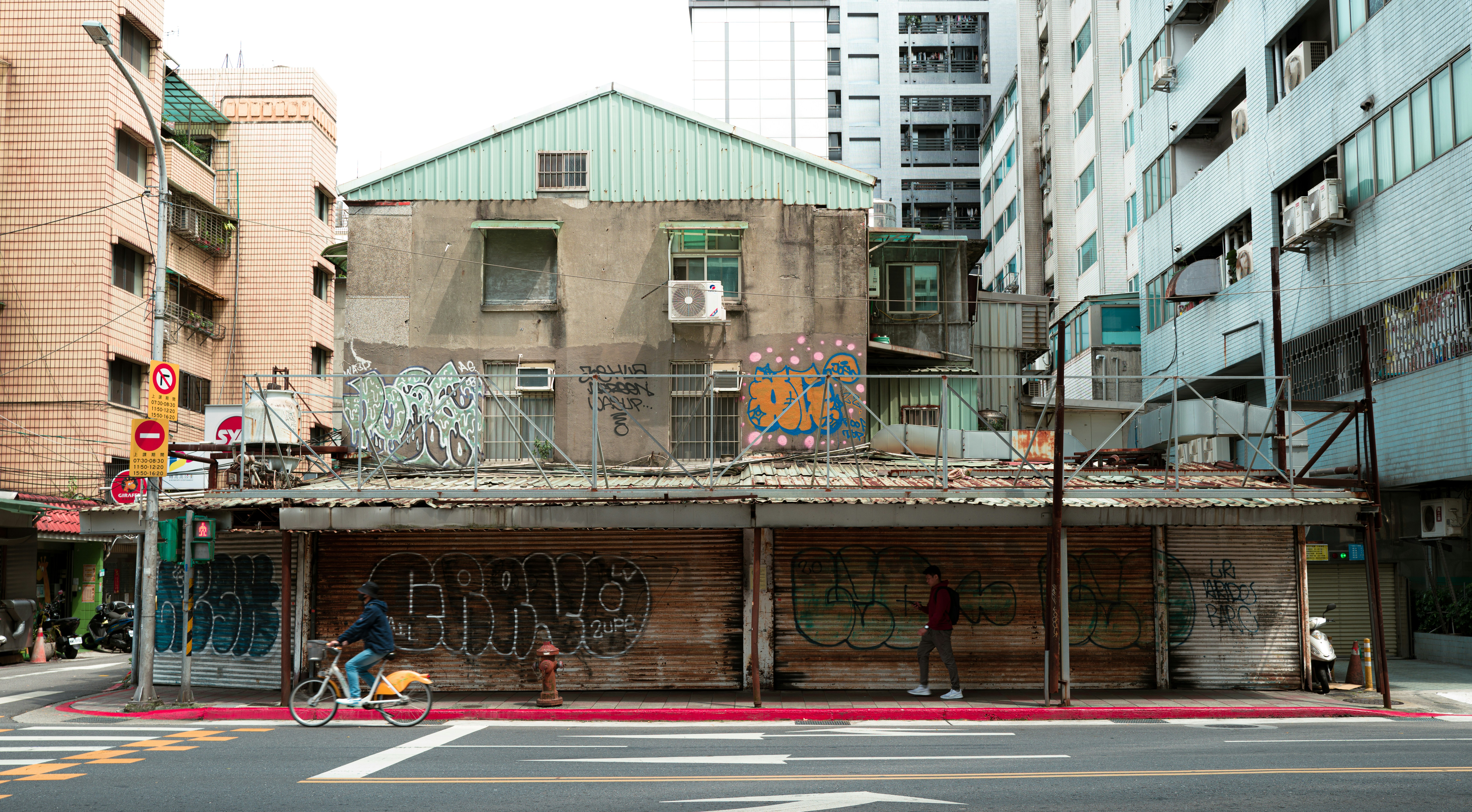 Urban Alleyfront Fade: Graffiti, Windows, and a Quiet Pedestrian