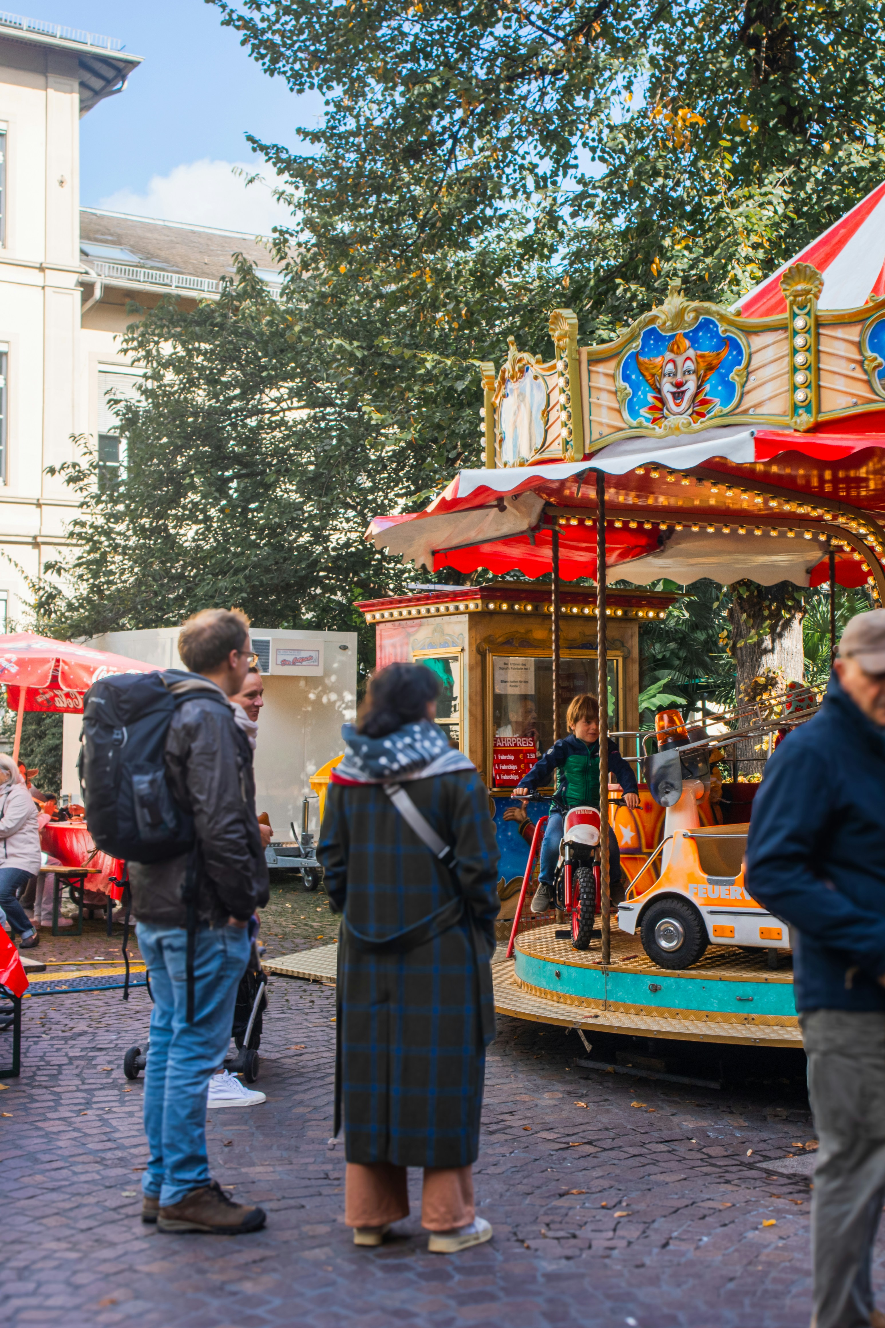 Carousel in the Square: People Queue by a Lively Midday Ride