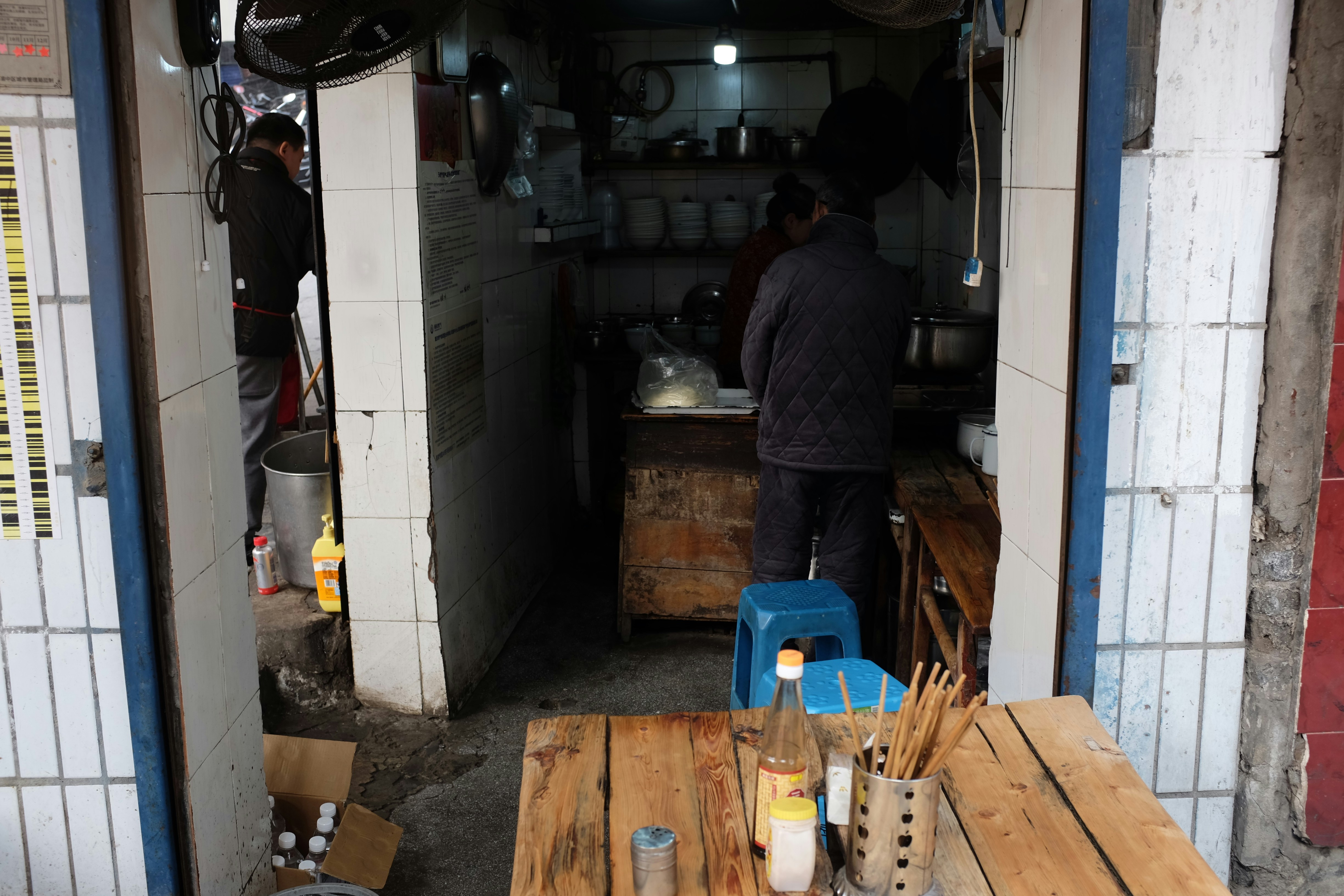 Open Kitchen at Dusk: Wooden Tables and Busy Backroom