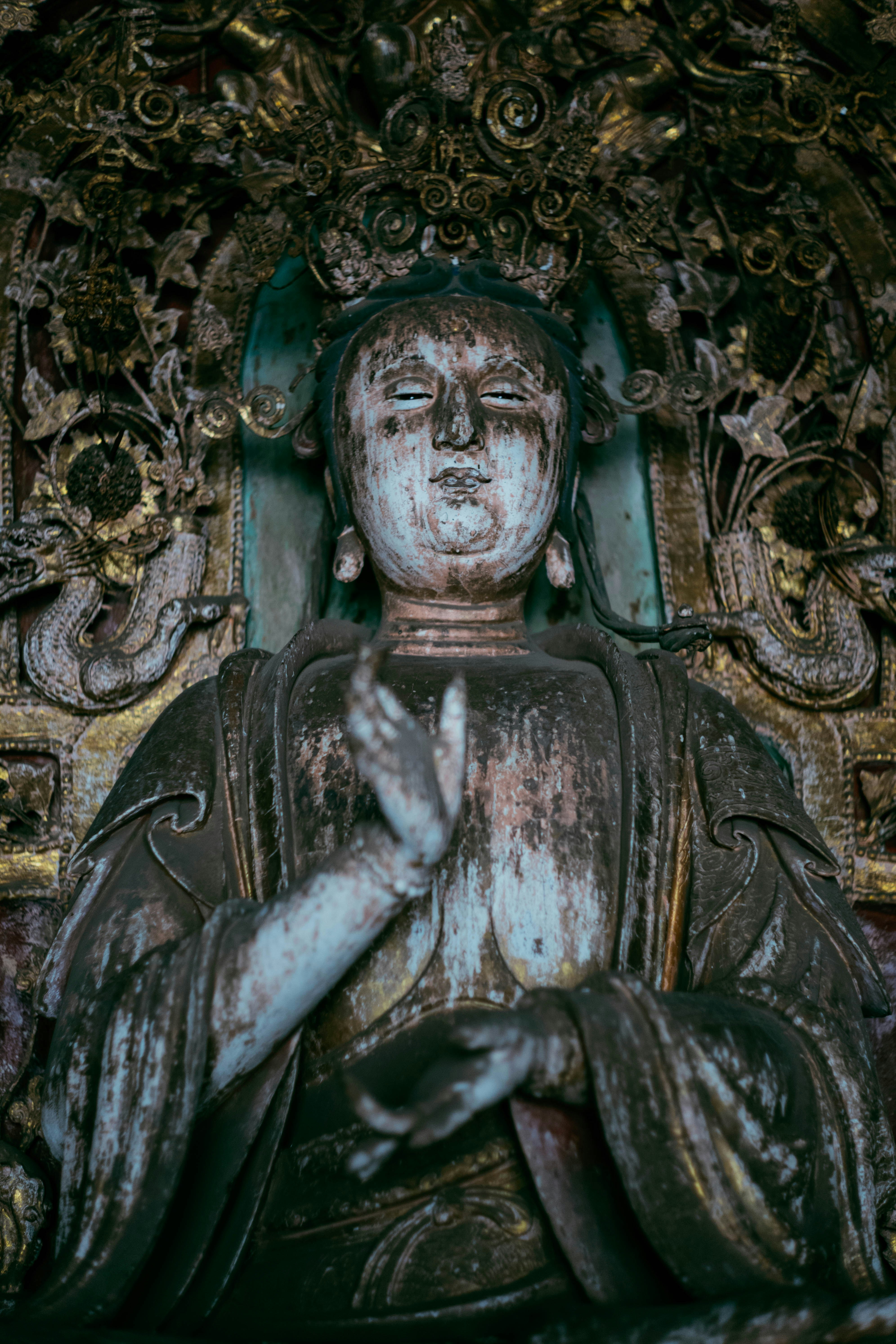 Prayerful Gaze: A Weathered Buddha amid Ornate Carvings