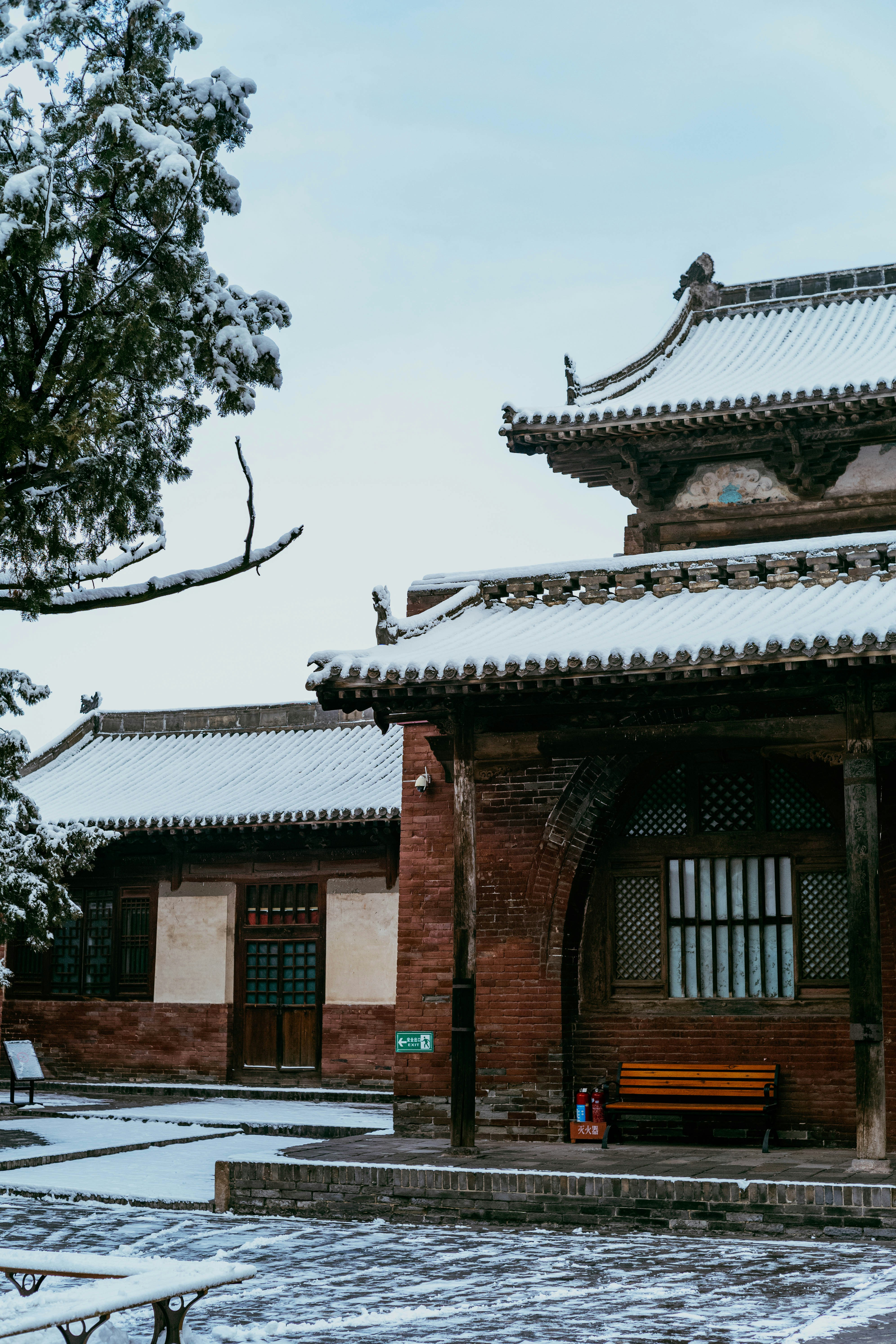 Snow-kissed Temple Courtyard: Red Brick Rooflines in Winter Light