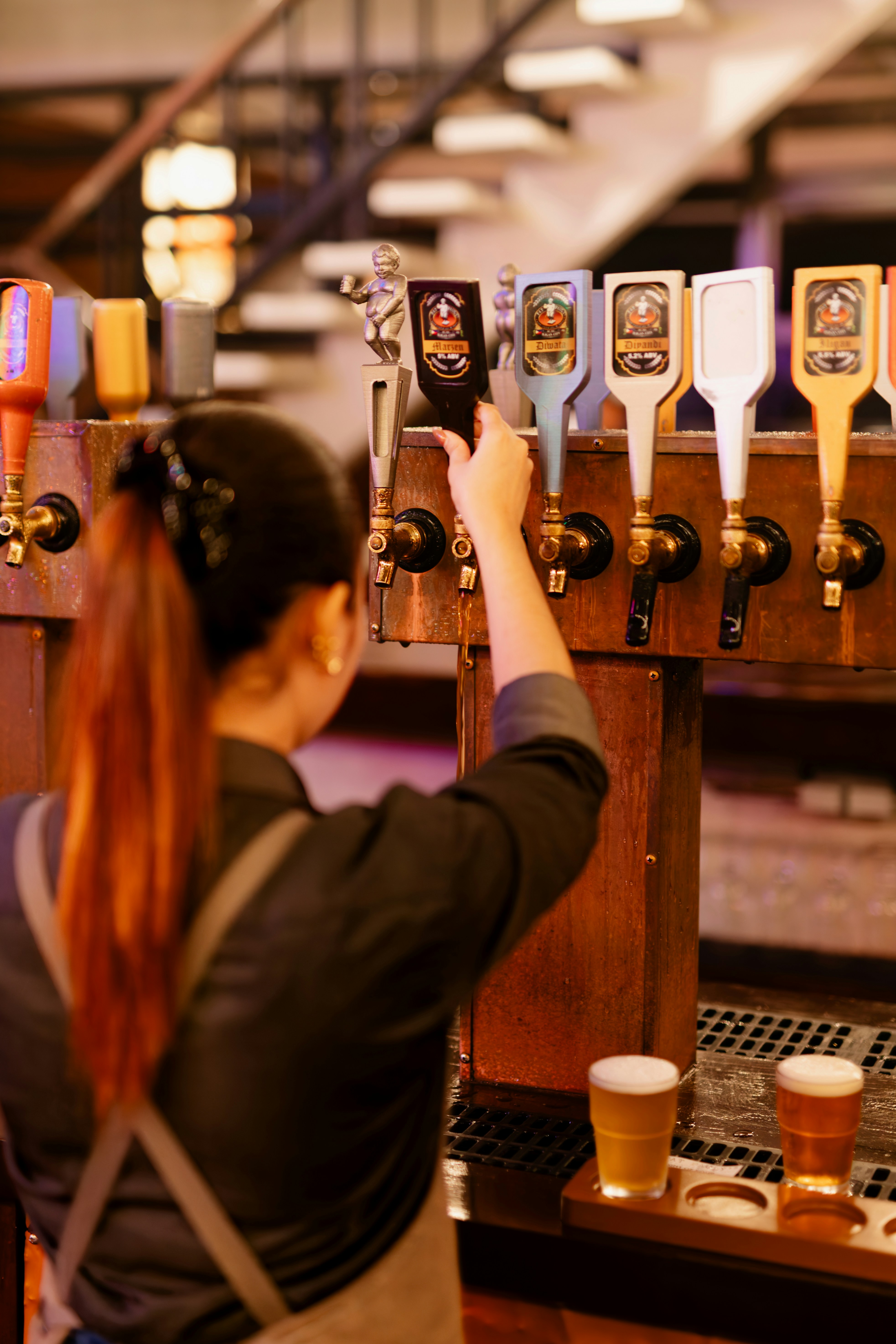 Draft taps and a focused pour: a bar-side barista works the taps
