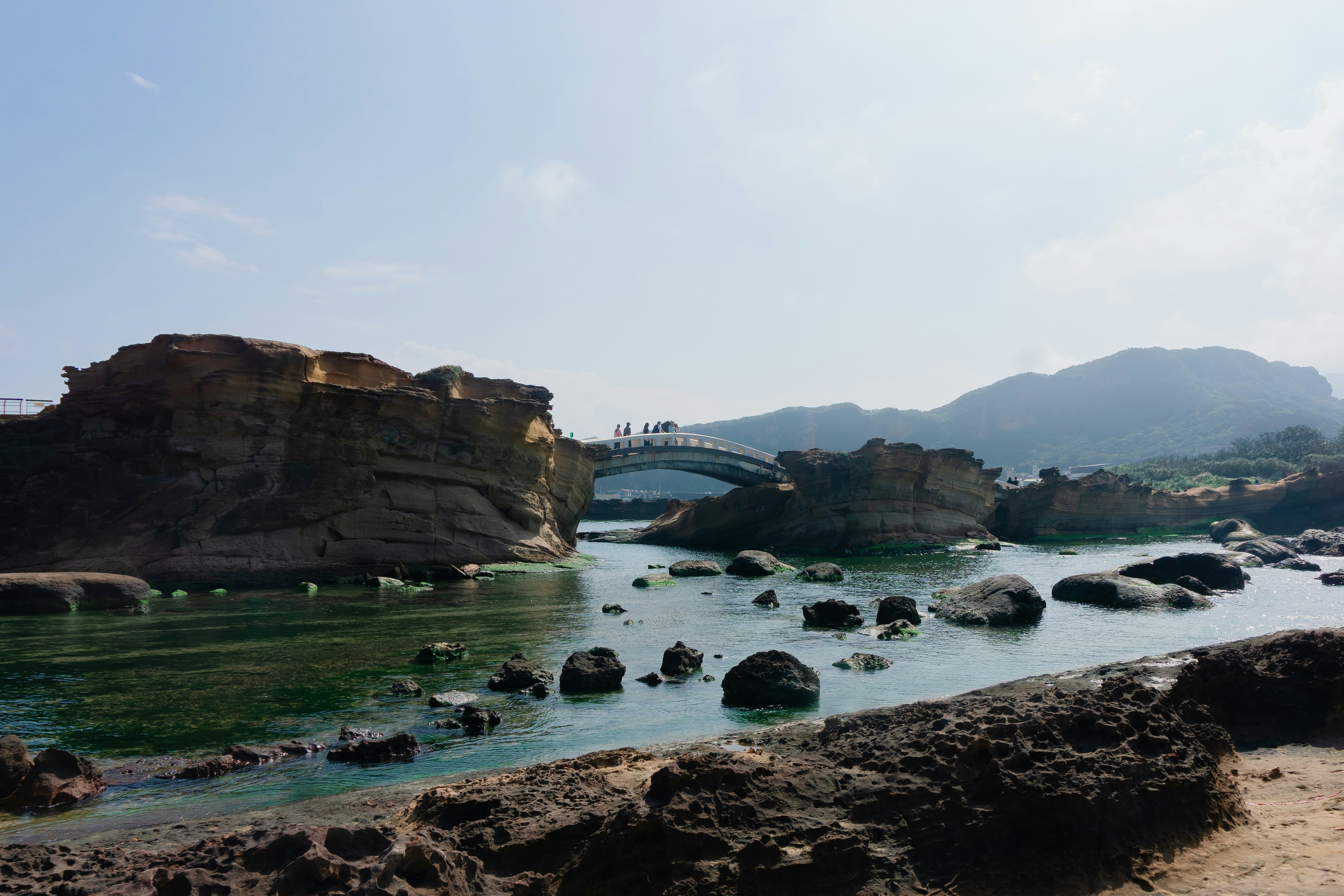 Arched Bridge Between Weathered Cliffs Over Quiet Tide