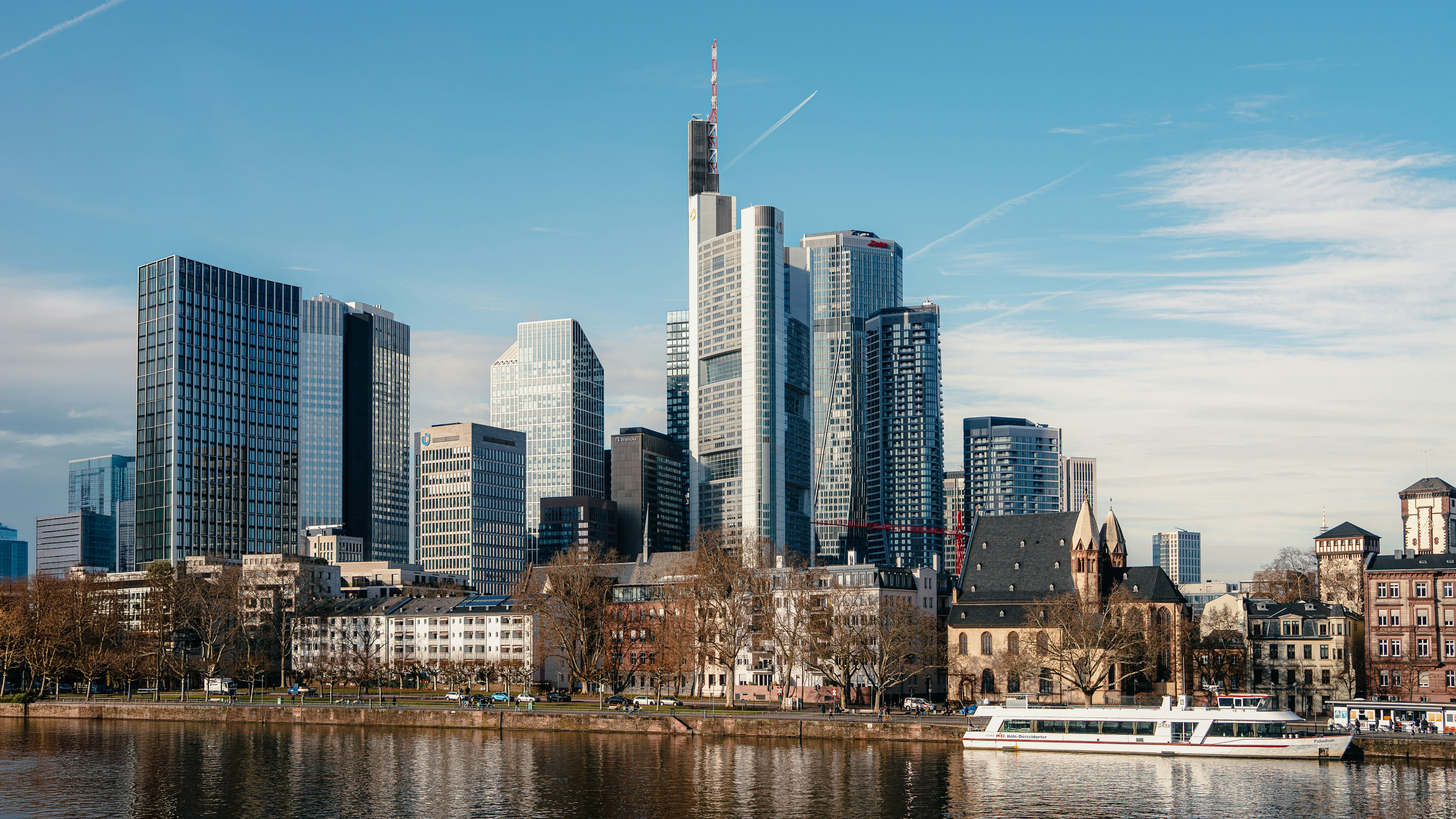 Modern skyscrapers and historic buildings by a river.