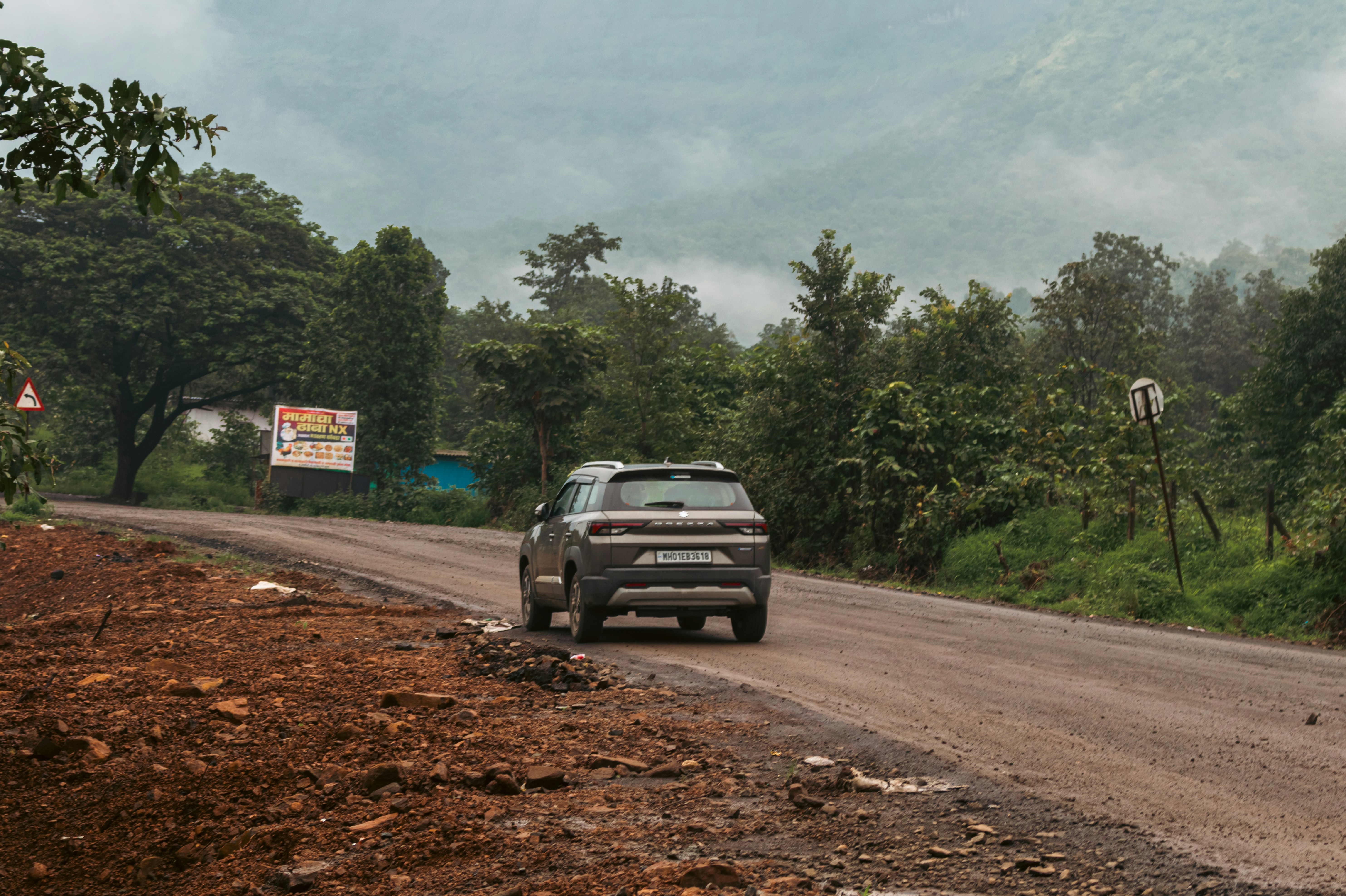 Rover on the Rural Road: A Car Traverses the Uneven Asphalt to a Green Horizon