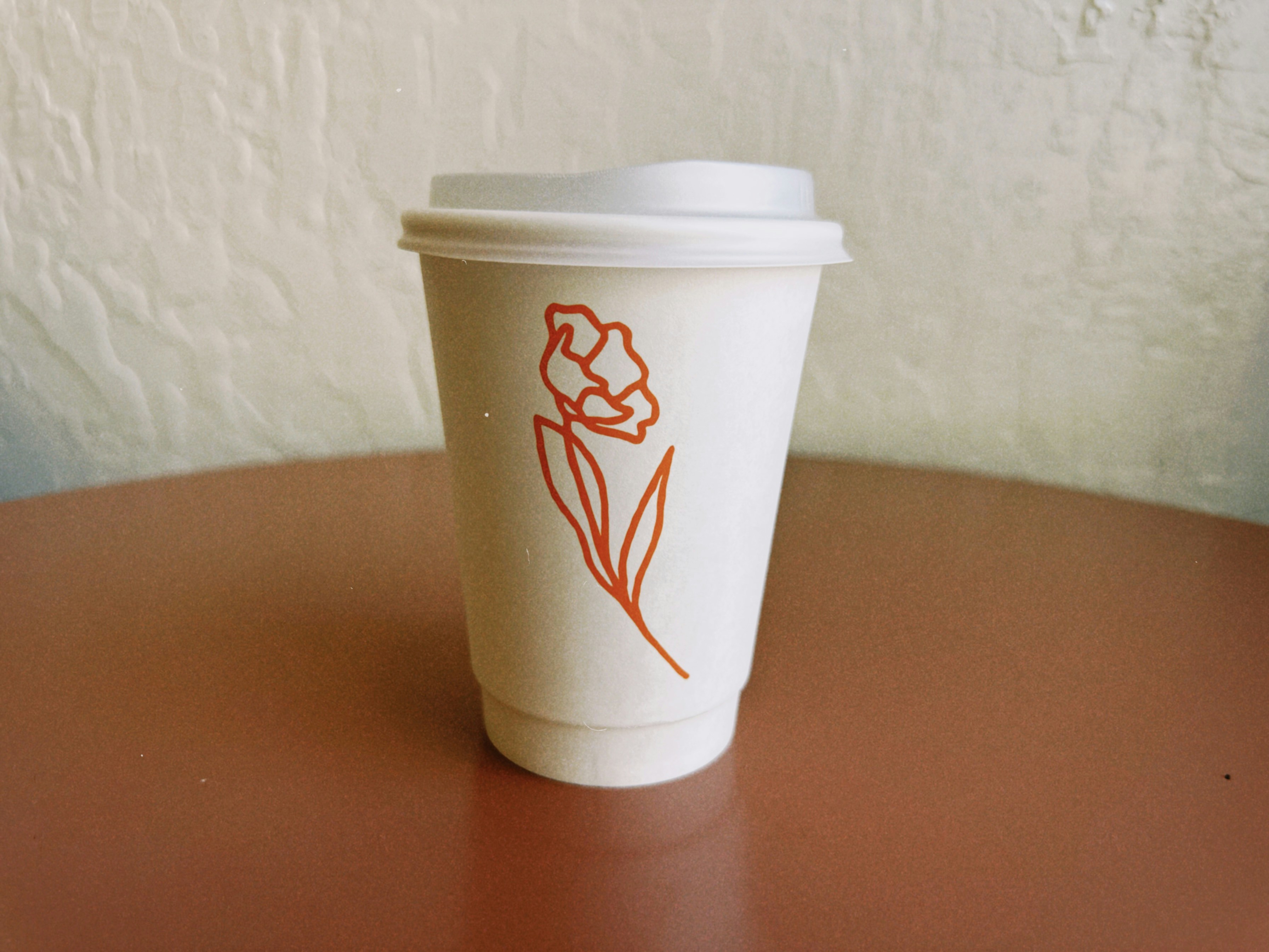 Minimalist takeaway: a lone illustrated cup on a warm table
