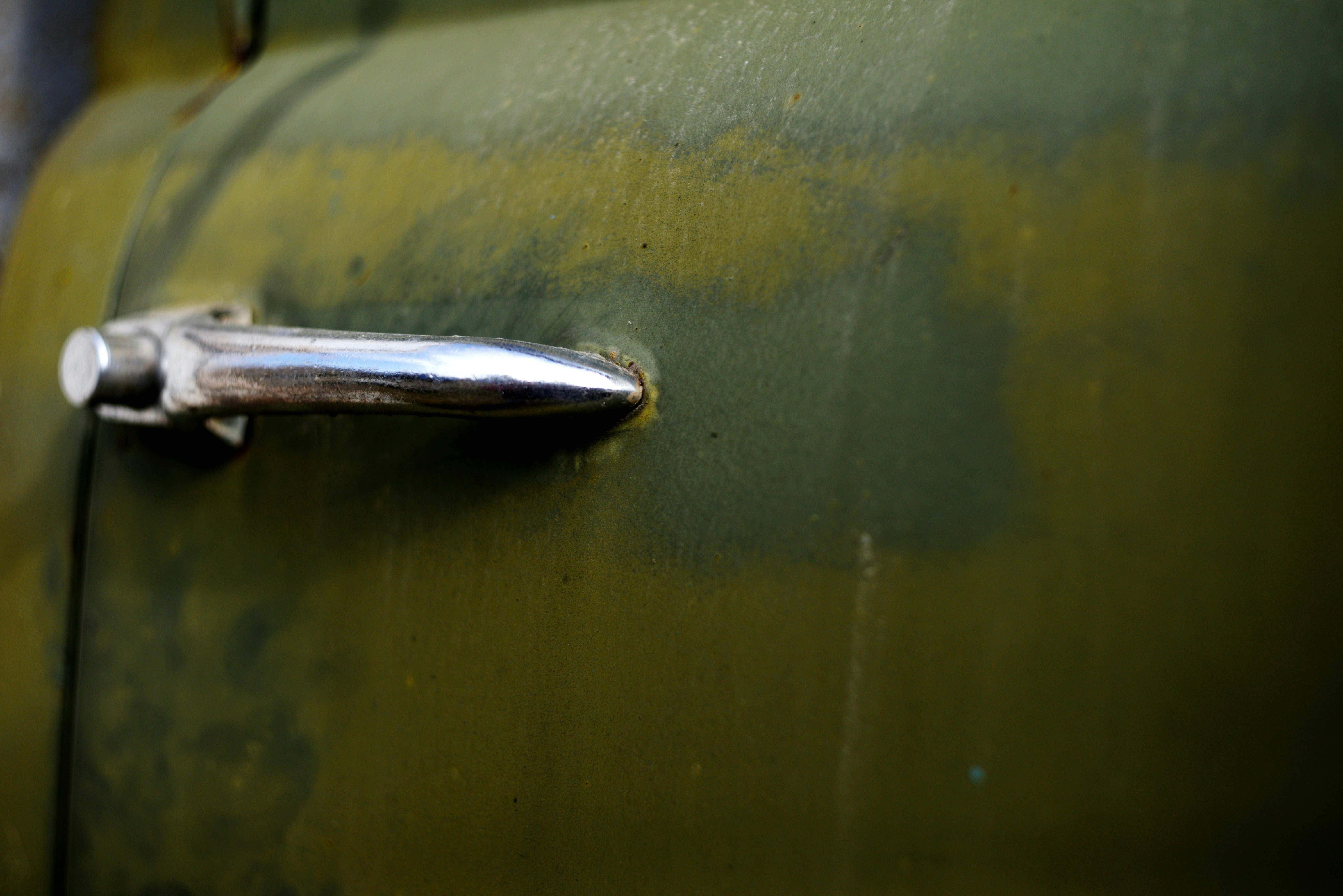 Weathered Chrome Sprite: A Vintage Car Door Handle in Timeworn Green