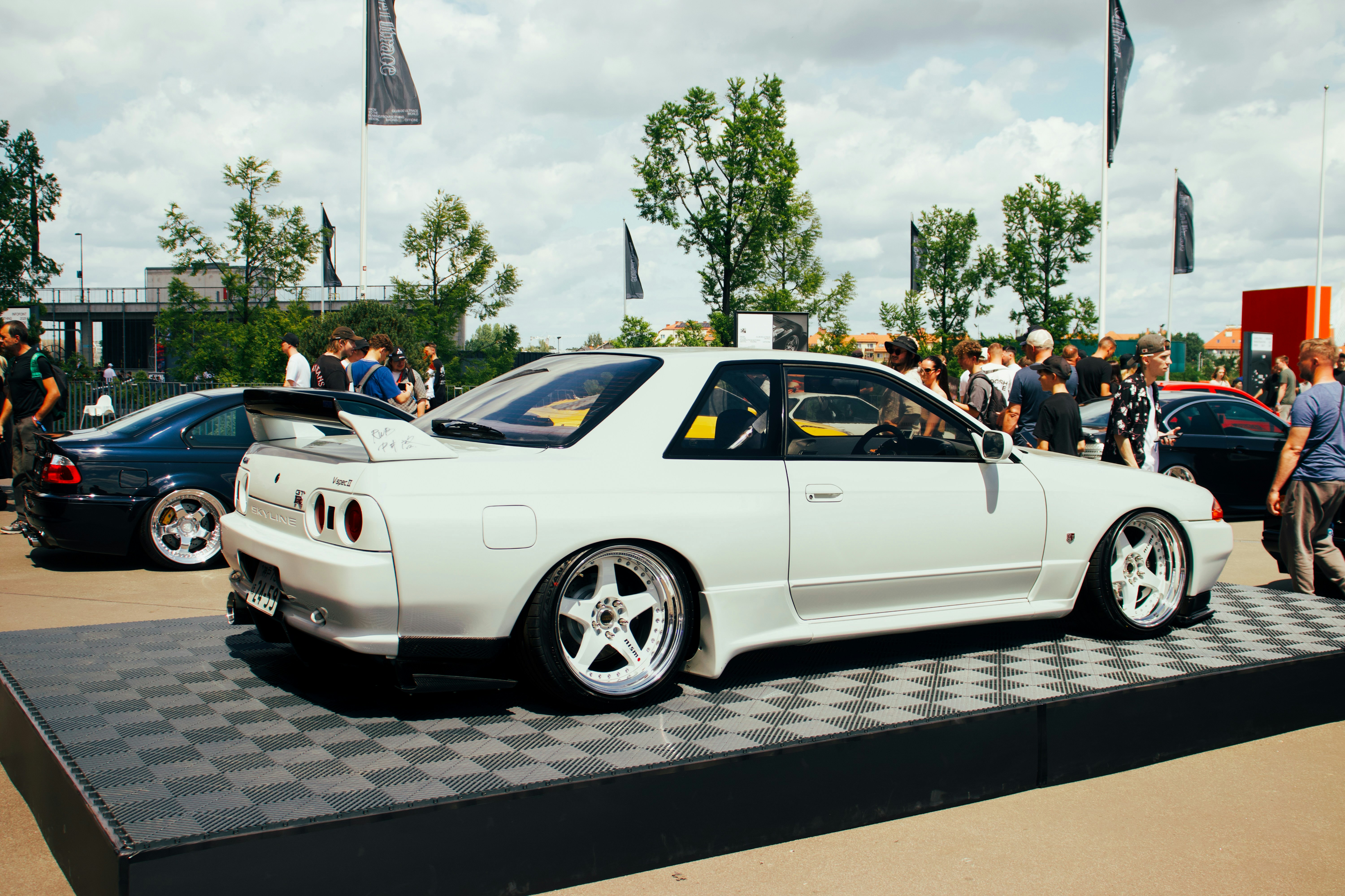 White Nissan Skyline on Elevated Display at Outdoor Car Show