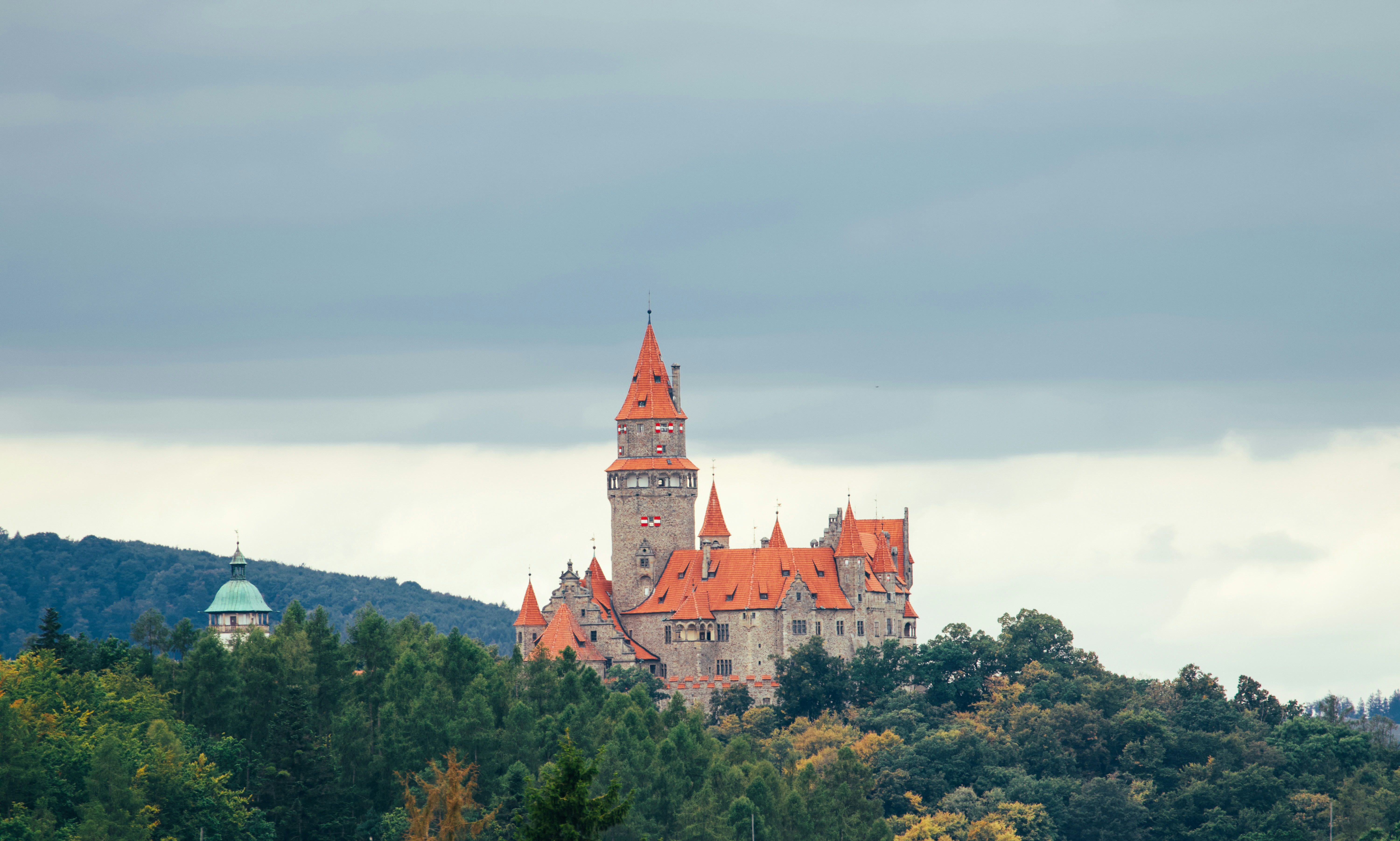 Castle on the Hill: A Red-Tiled Summit Resting Above Autumn Woods
