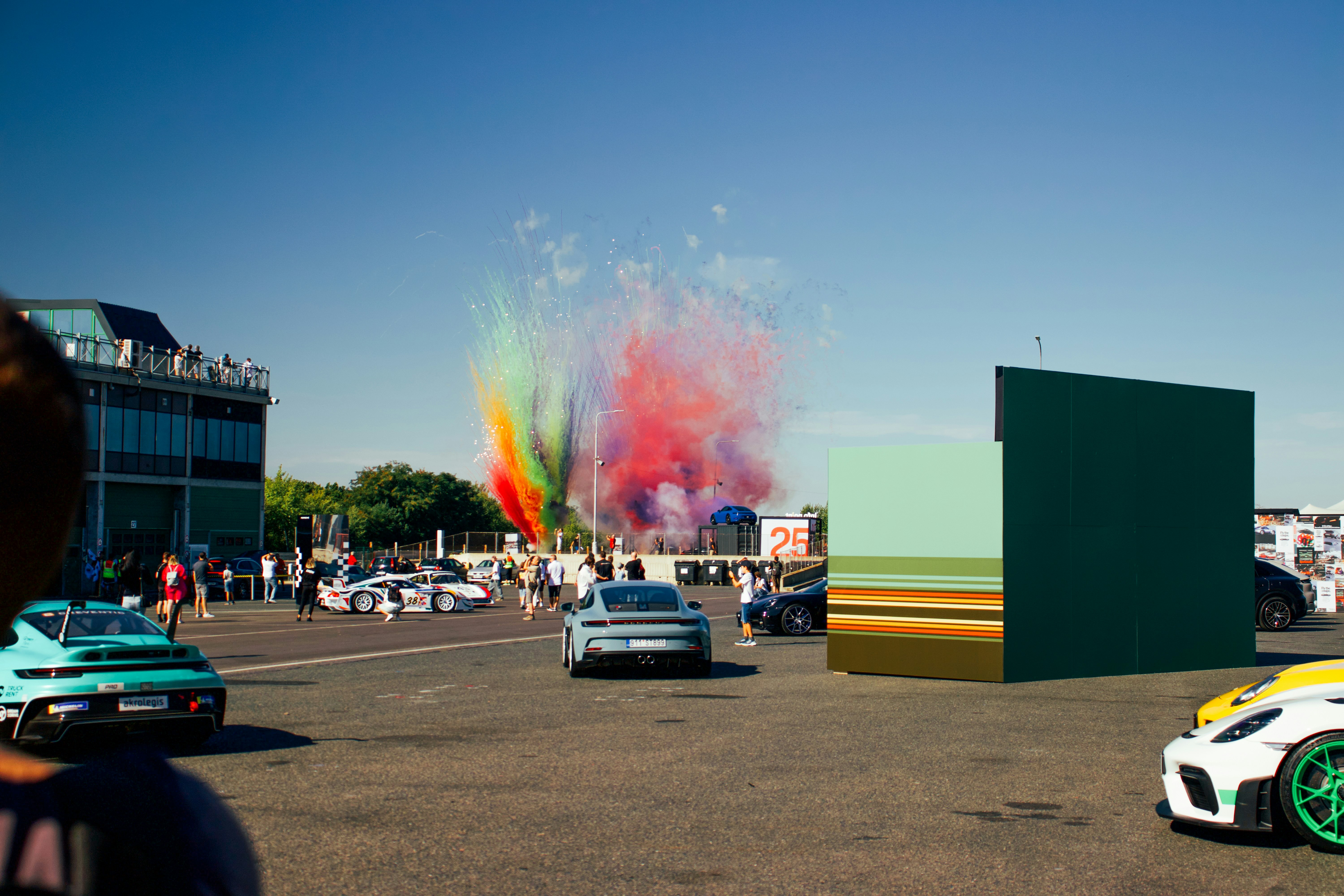 Colorful ignition: rainbow plume over a car show