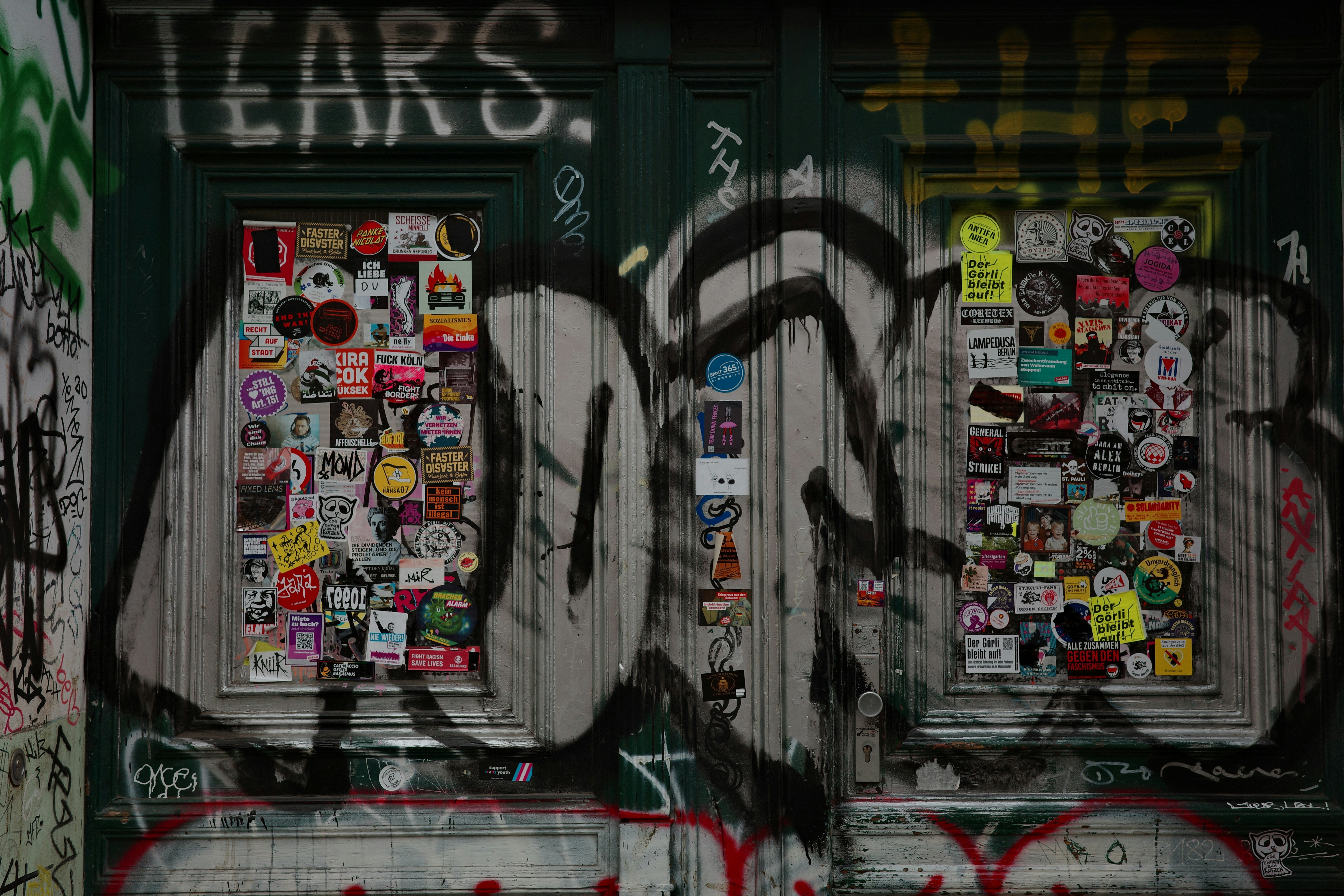 Stickered Doorways: A Graffiti-Layered Facade Between Two Windows