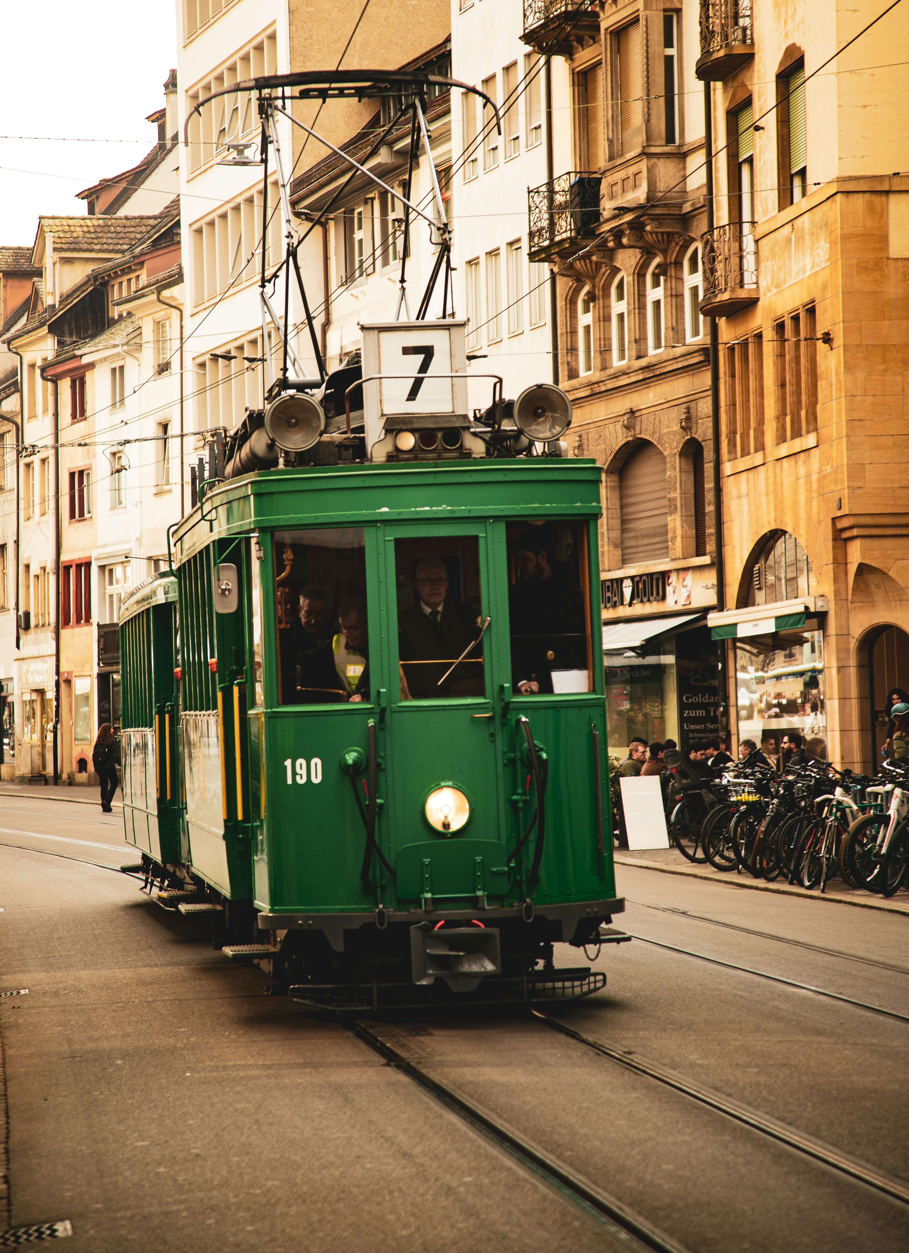 Green Tram Rounds the Corner Through a European Street