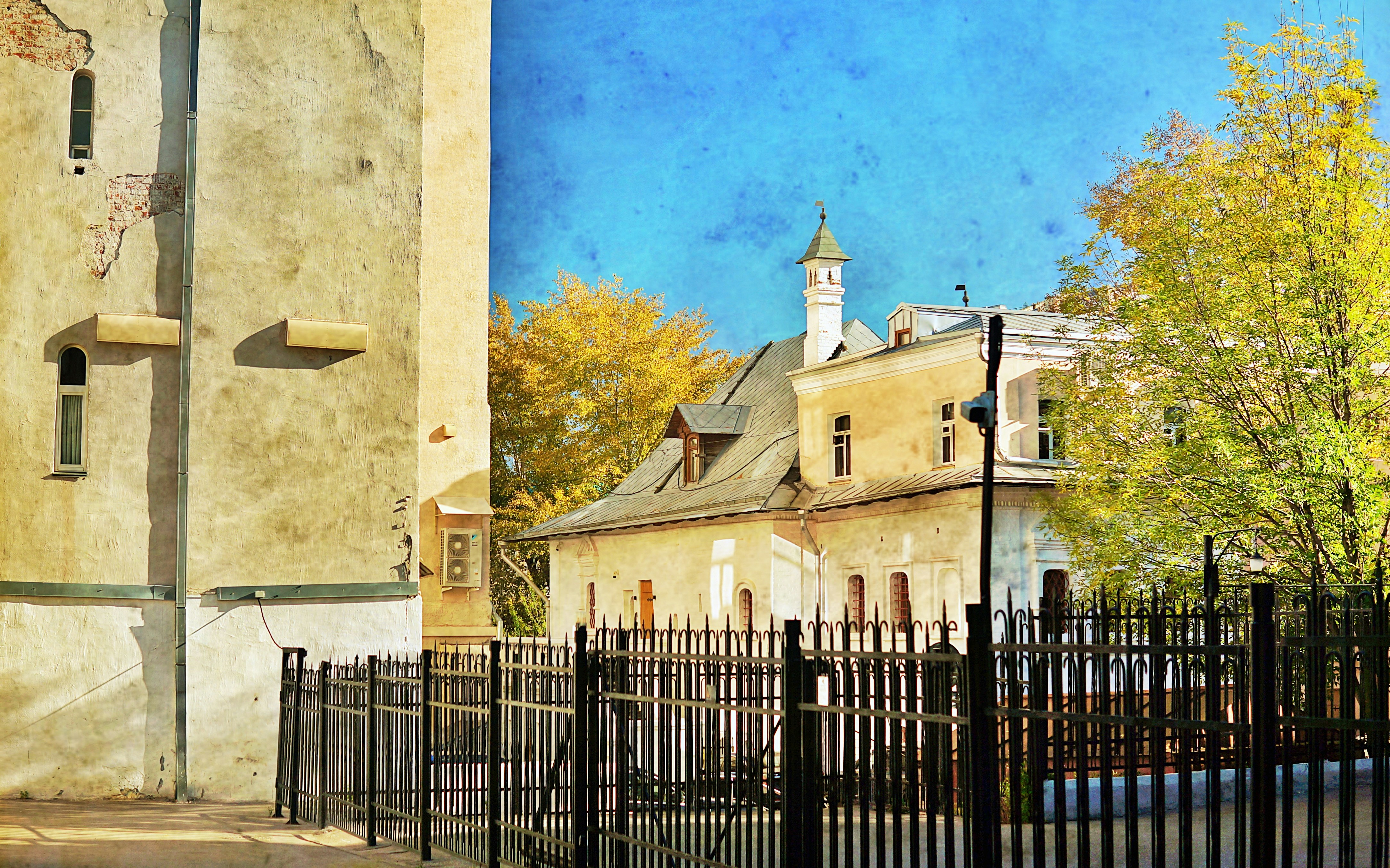 Sunlit Courtyard Through a Wrought-Iron Fence