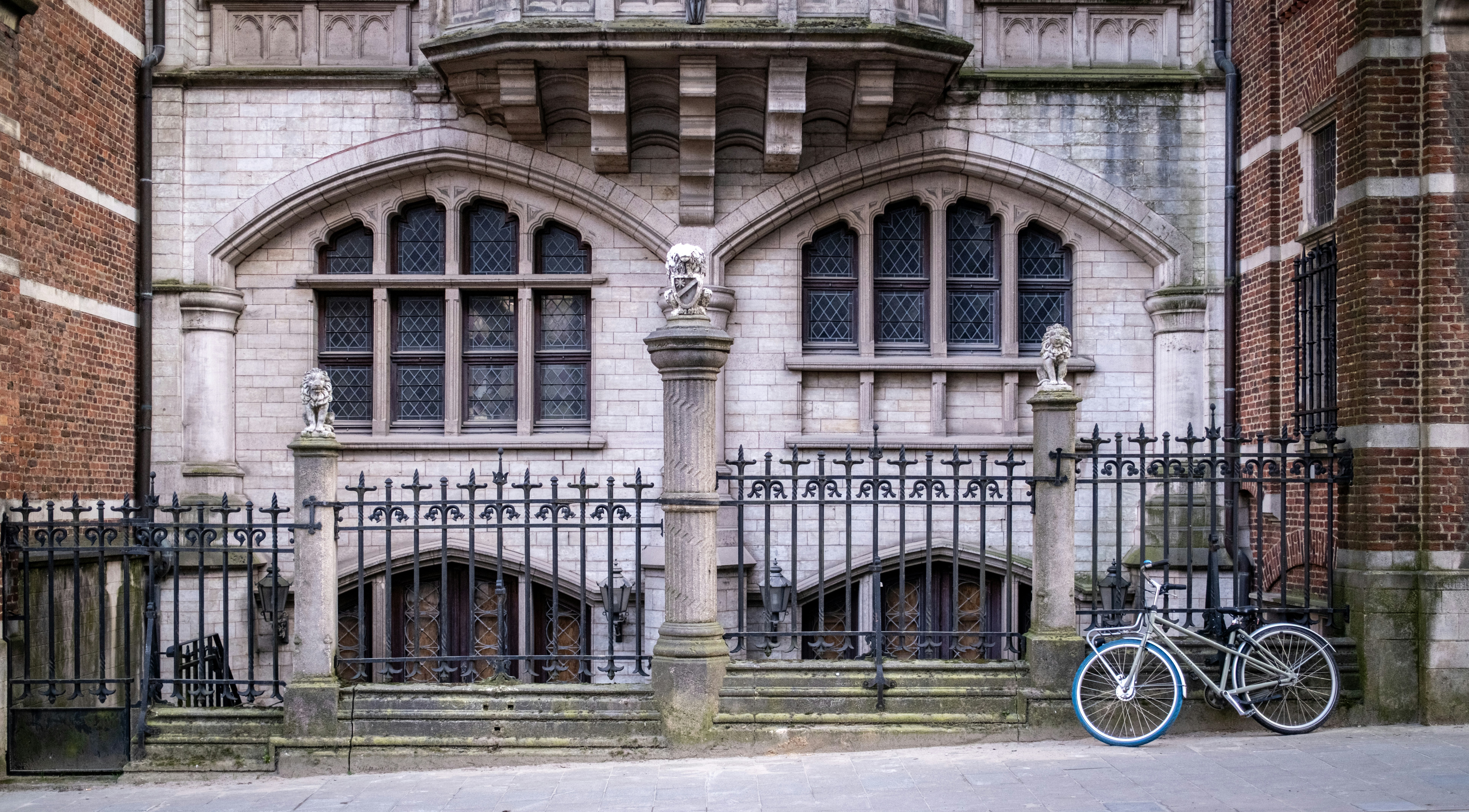 Iron Gate and Blue Bicycle: Quiet Campus Facade with Historic Ironwork