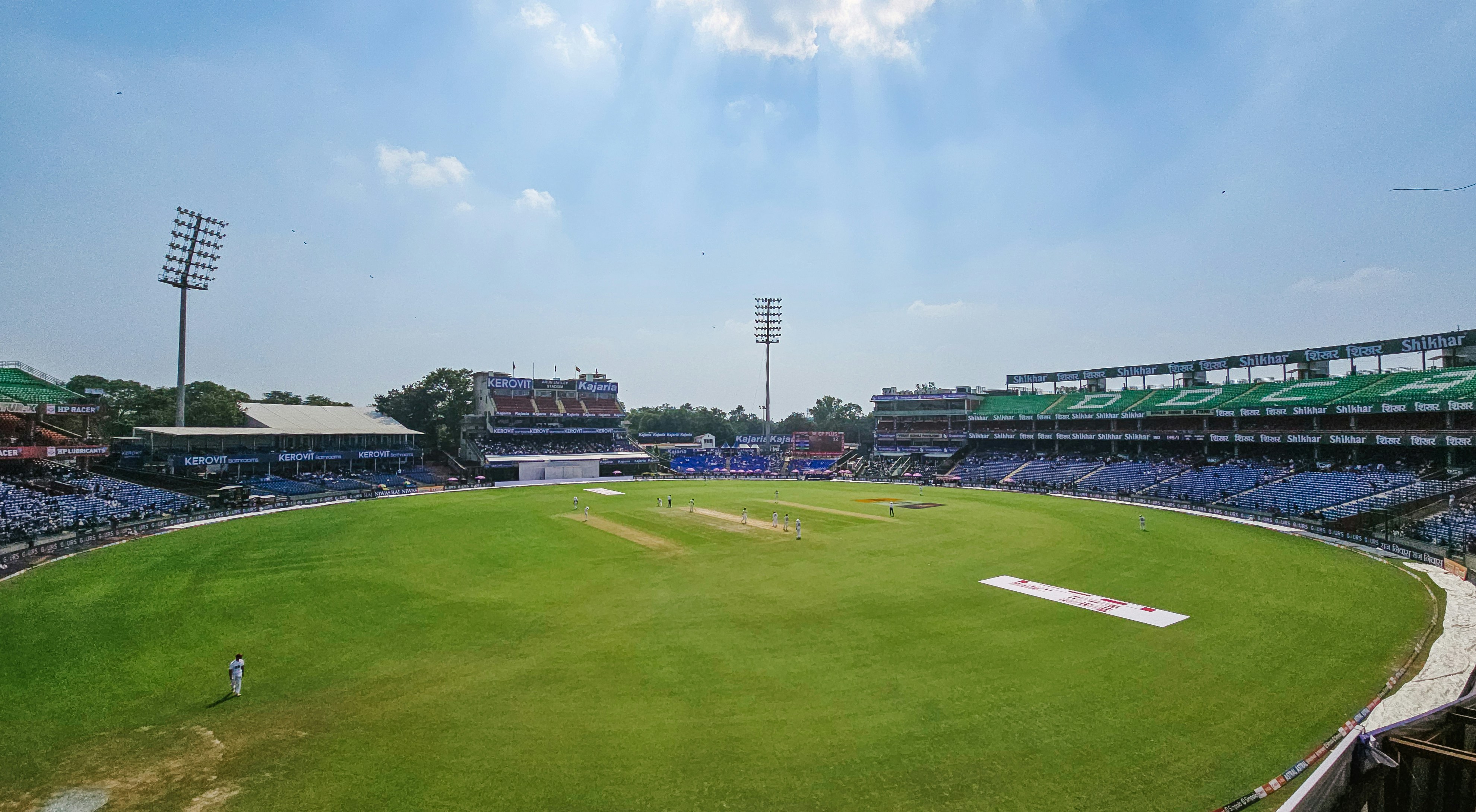 A wide panoramic view of Arun Jaitley cricket stadium in Delhi, India during a live match, showing the full field, pitch, and surrounding stands. The expansive perspective highlights the scale of the venue and the game in progress.