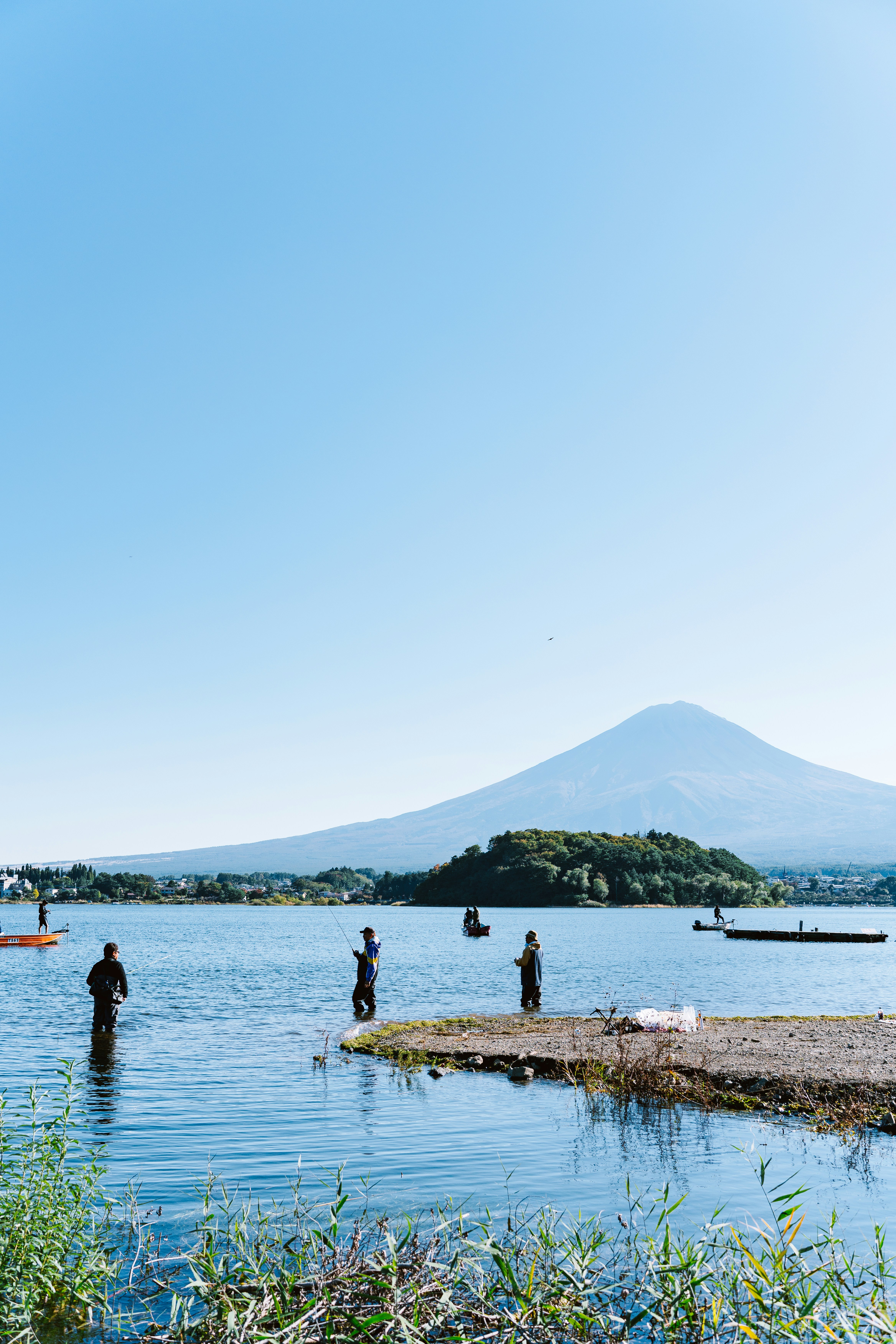 Mt. Fuji silhouette over a tranquil lake with anglers at the shoreline