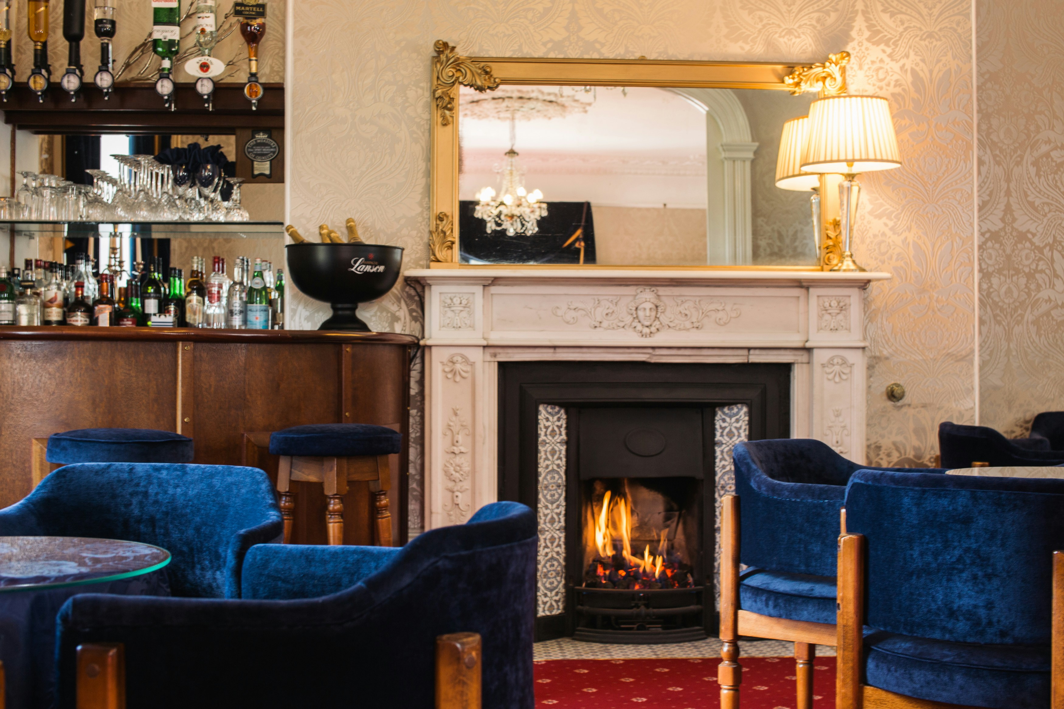 Cozy Barroom Glow: Velvet Seats, Marble Mantel, and Fireplace Light