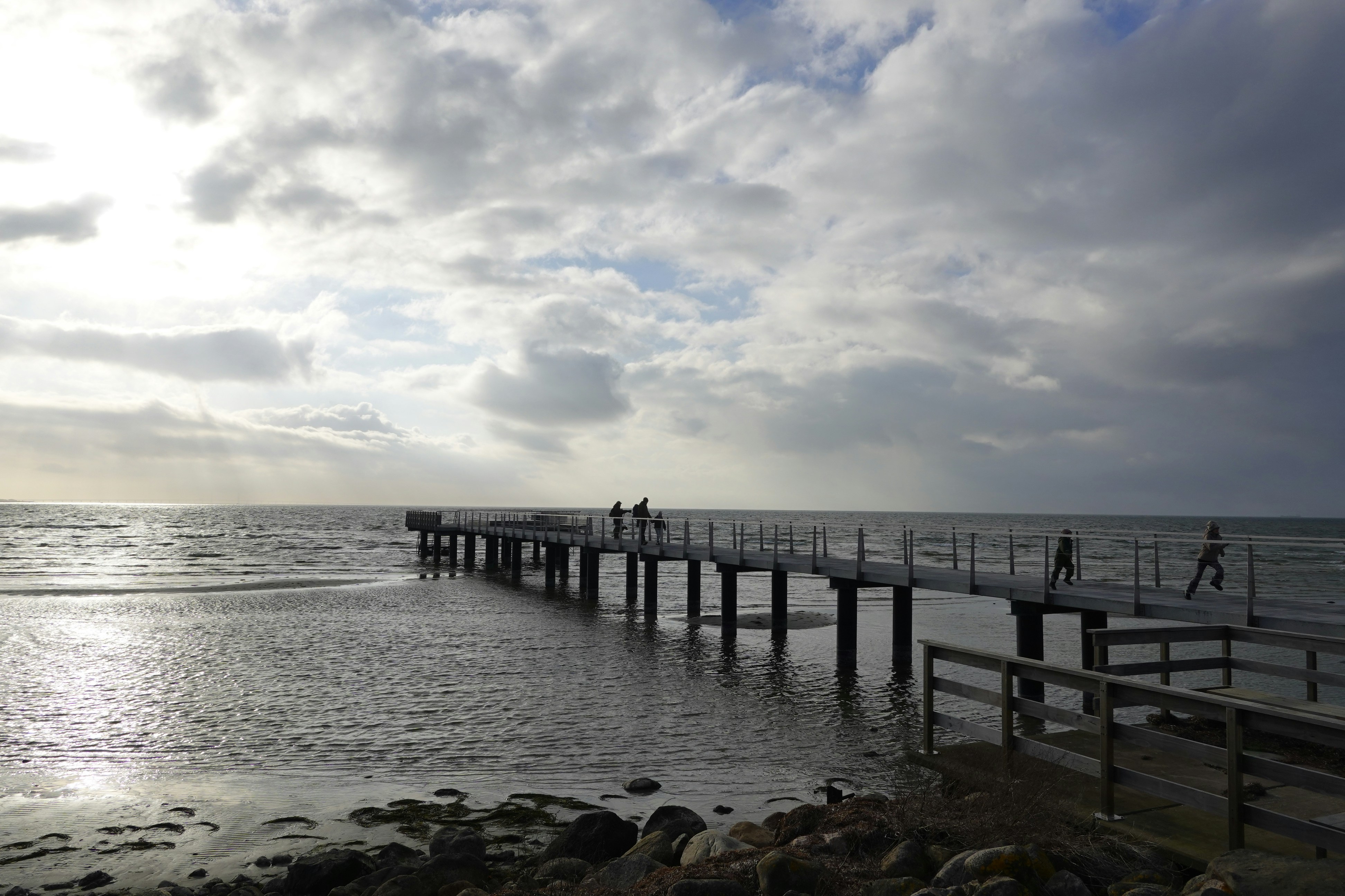 Pier silhouette toward the horizon under a stormy sea