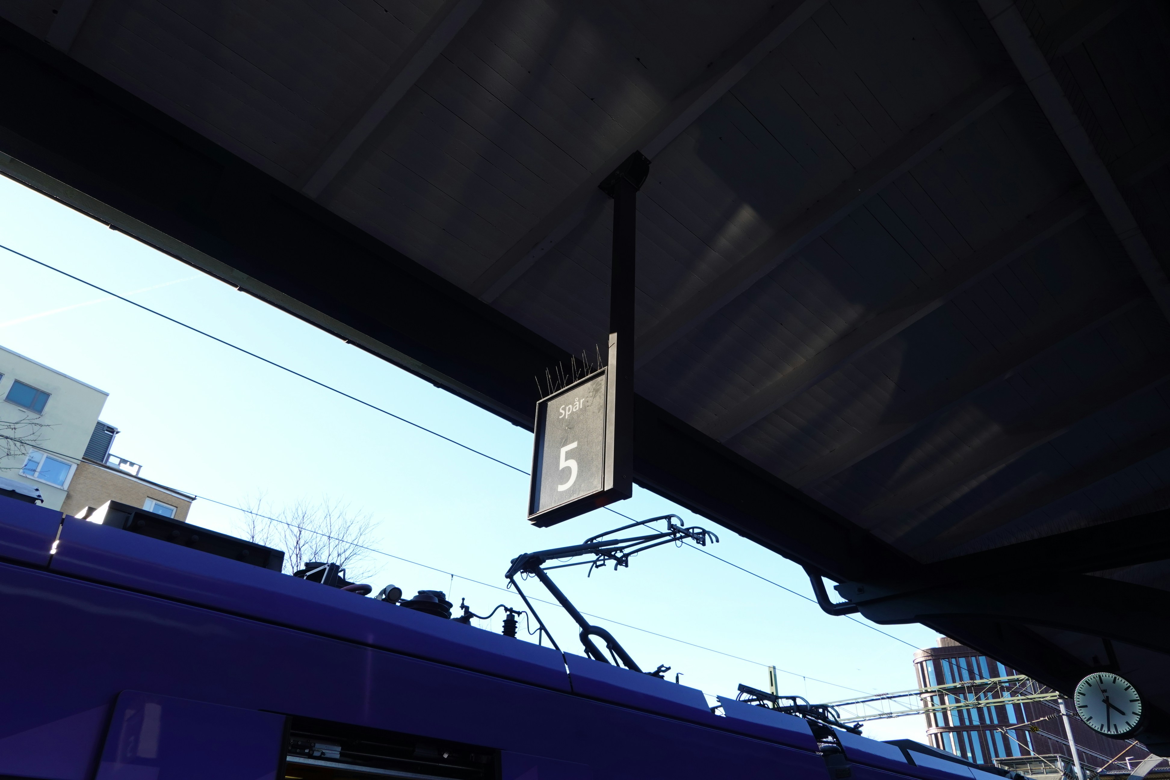 Platform Sign Above a Purple Streetcar in an Urban Canopy
