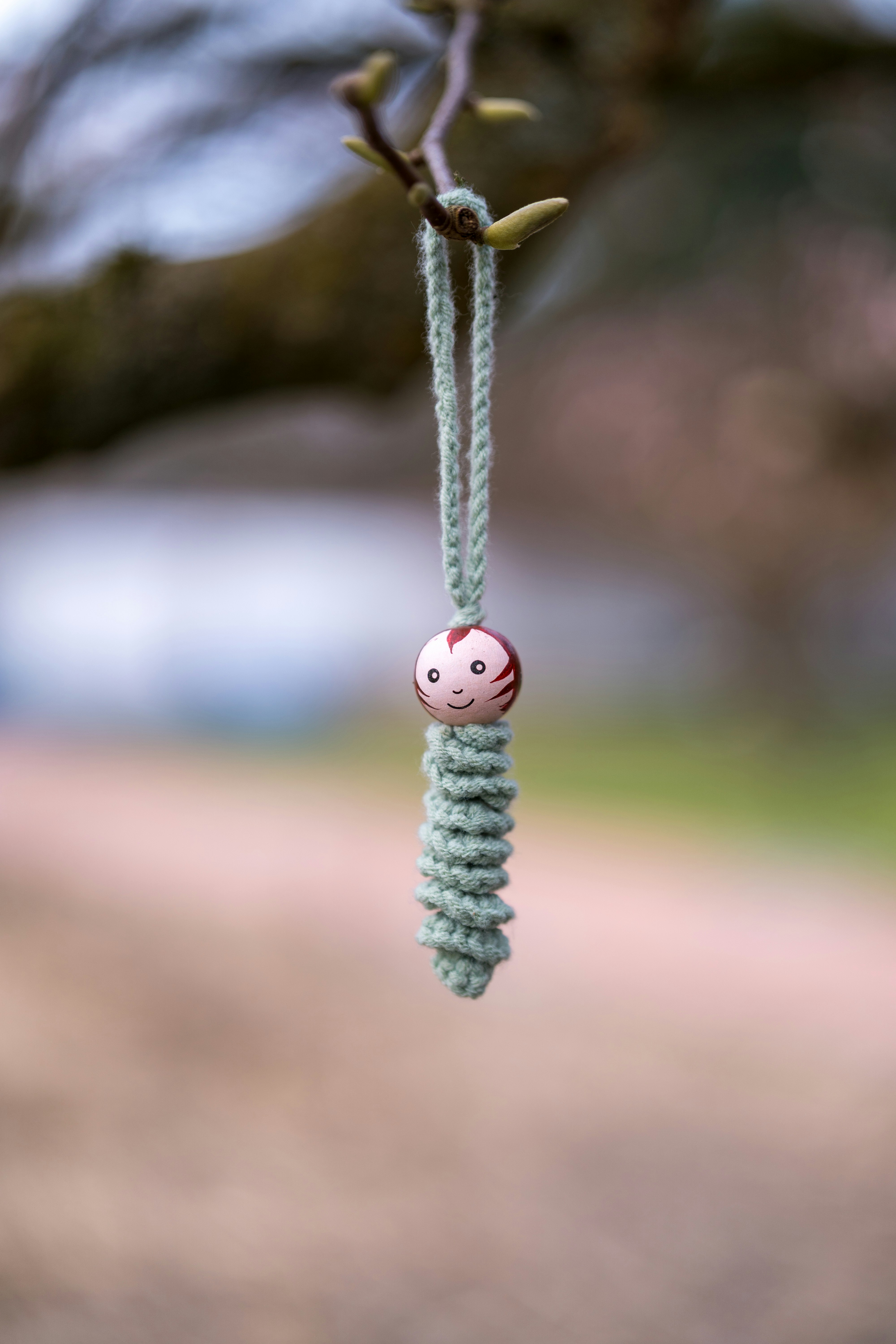 Hanging Hope: A Tiny Beaded Face on a Softly Coiled Pendant