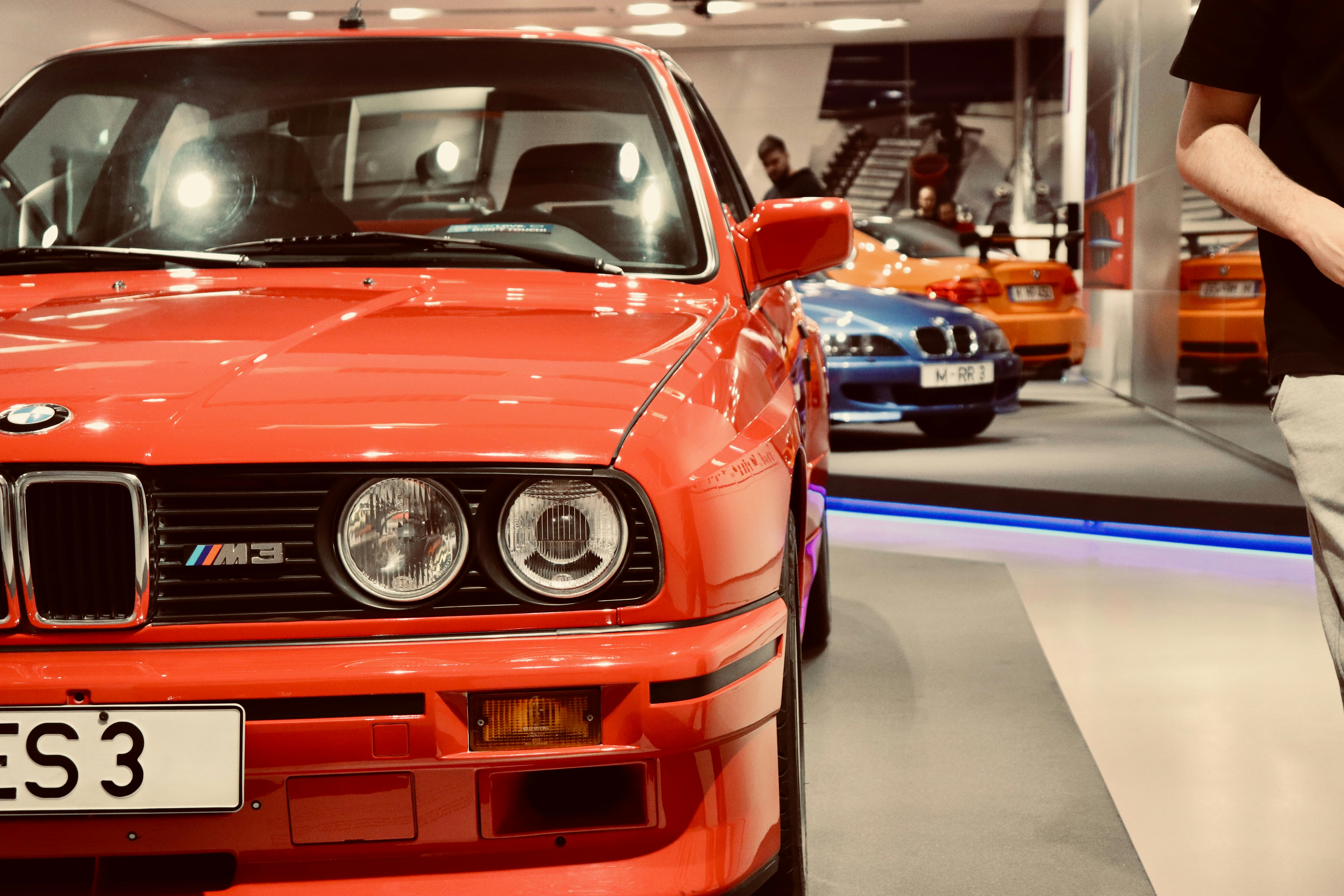 Red BMW M3 in a showroom: chrome glare and automotive lineup