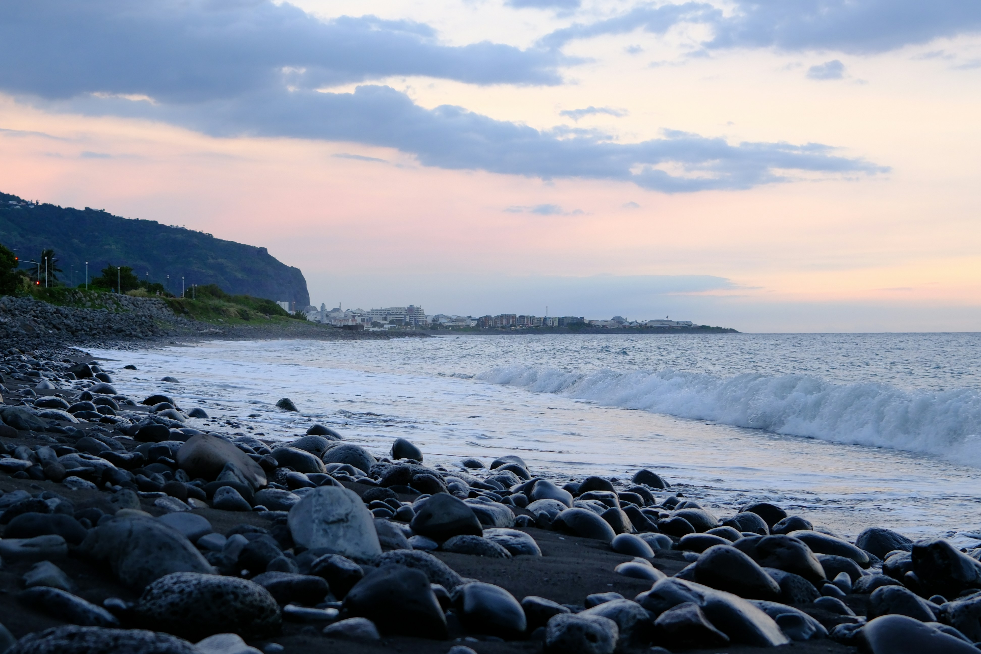 Pebble shoreline at dusk with distant headland