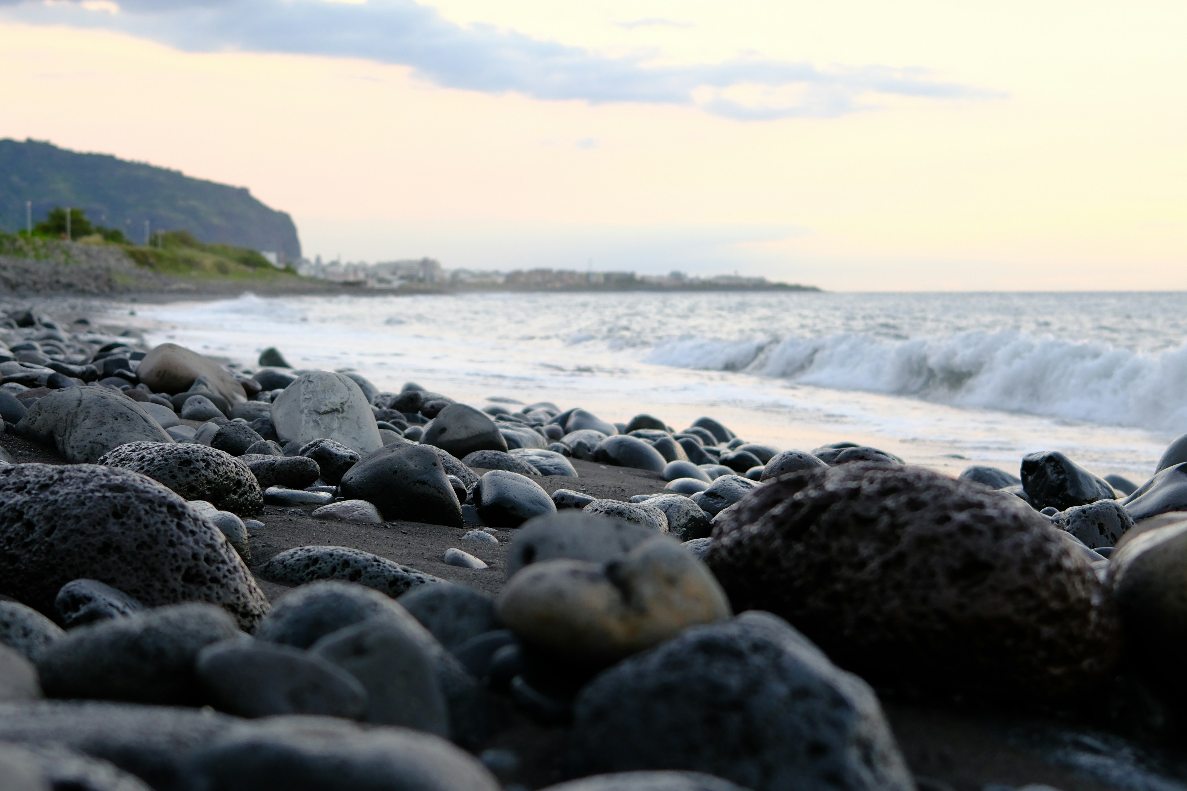 Pebble shoreline fading into the horizon with distant cliff