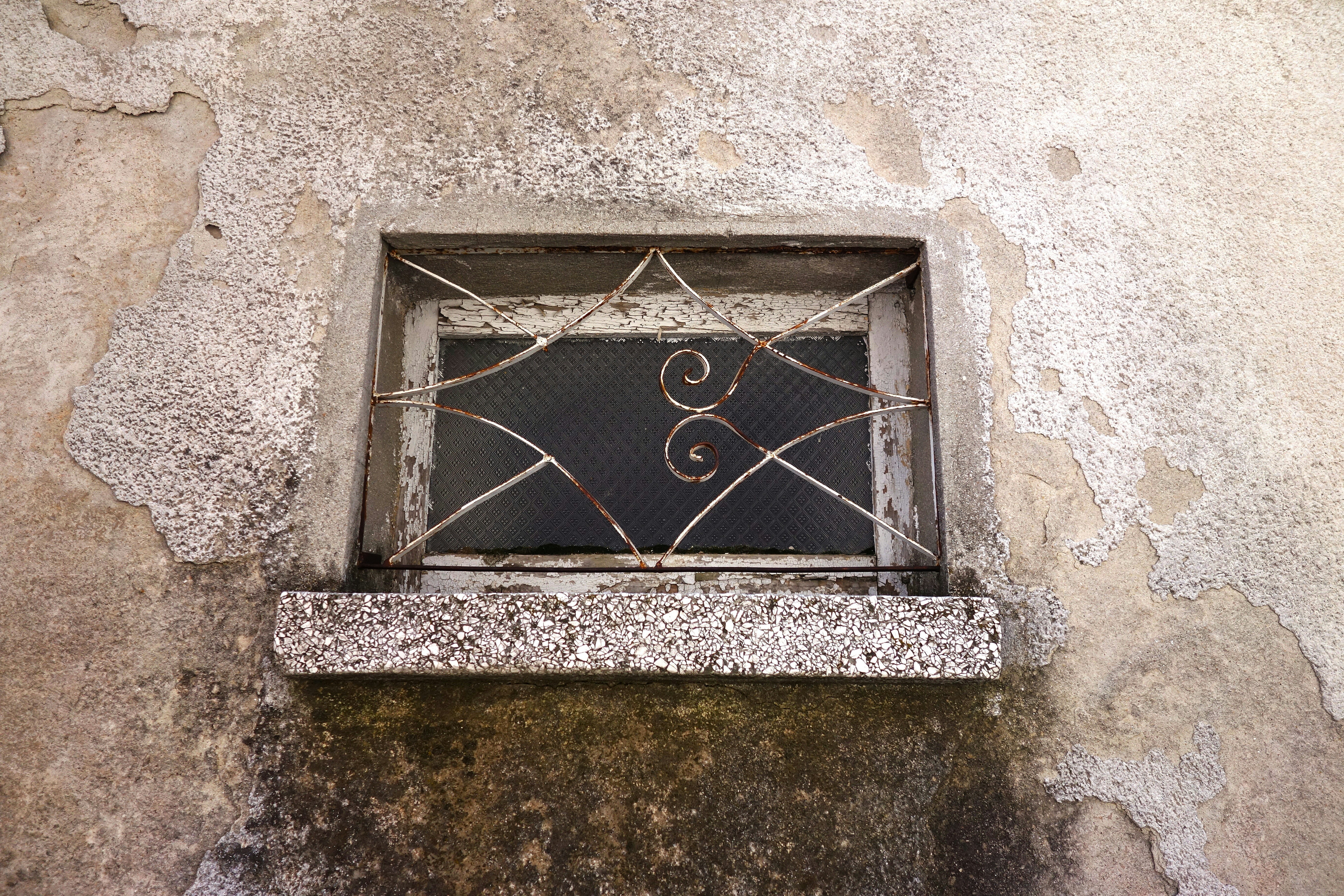 Worn Window Grilles on a Weathered Wall