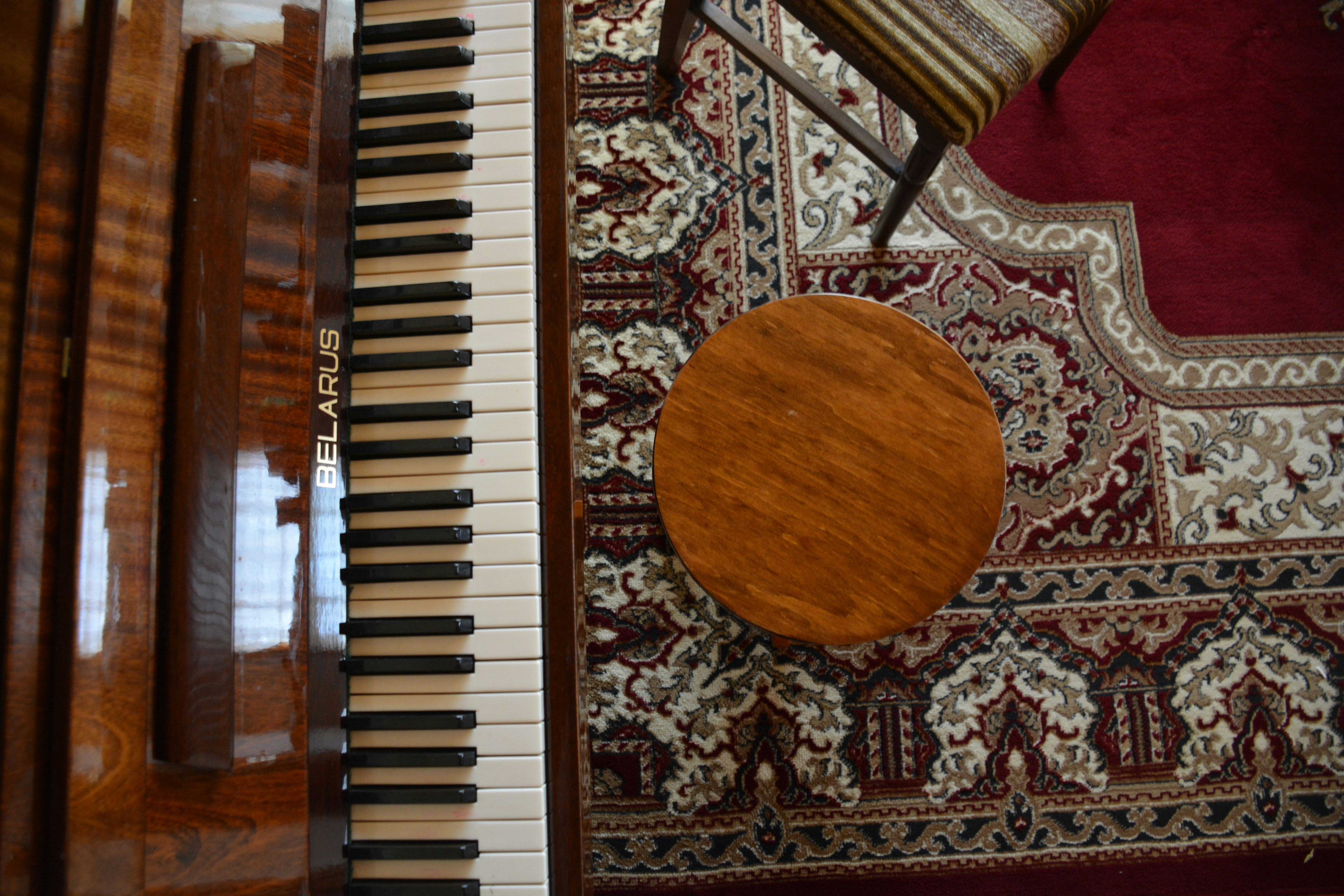 Overhead View: A Vintage Piano and Round Stool on an Ornate Rug