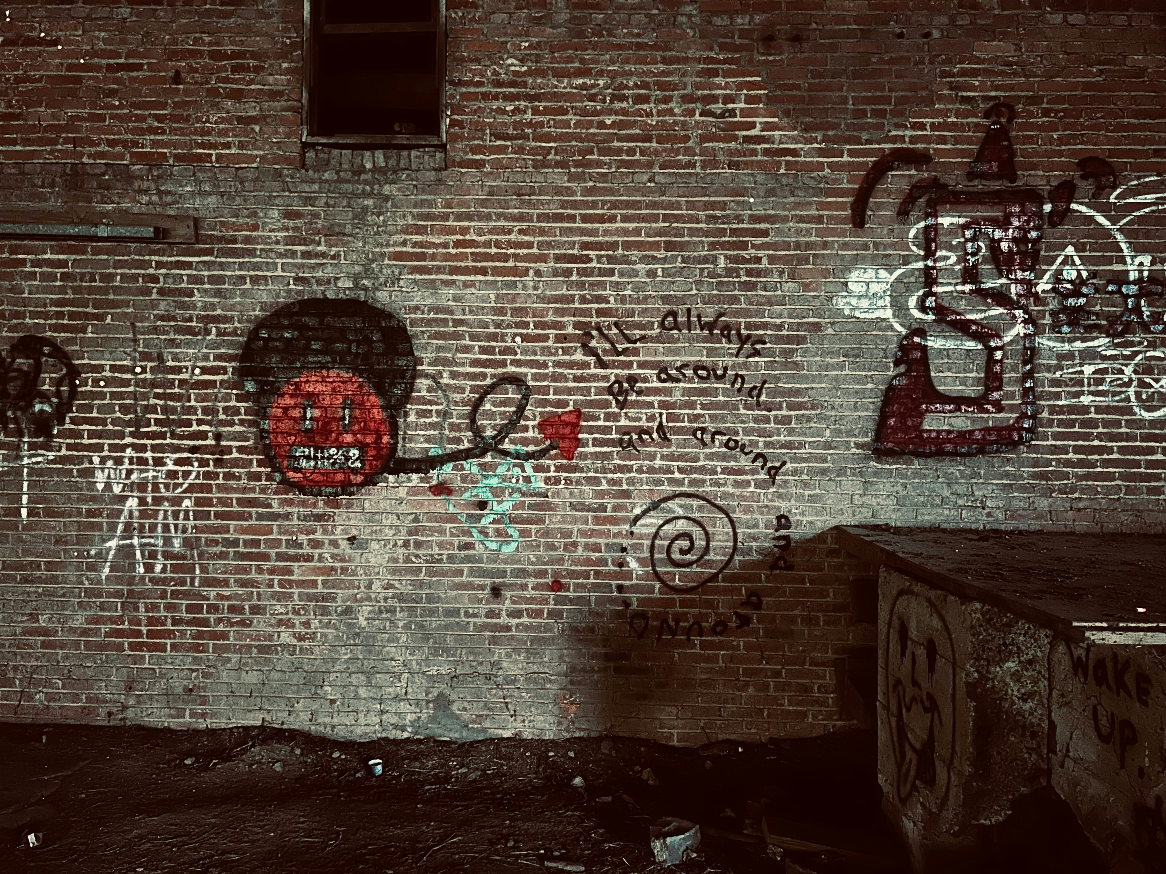 Red Smiley Graffiti and Circular Spiral on Weathered Brick Wall