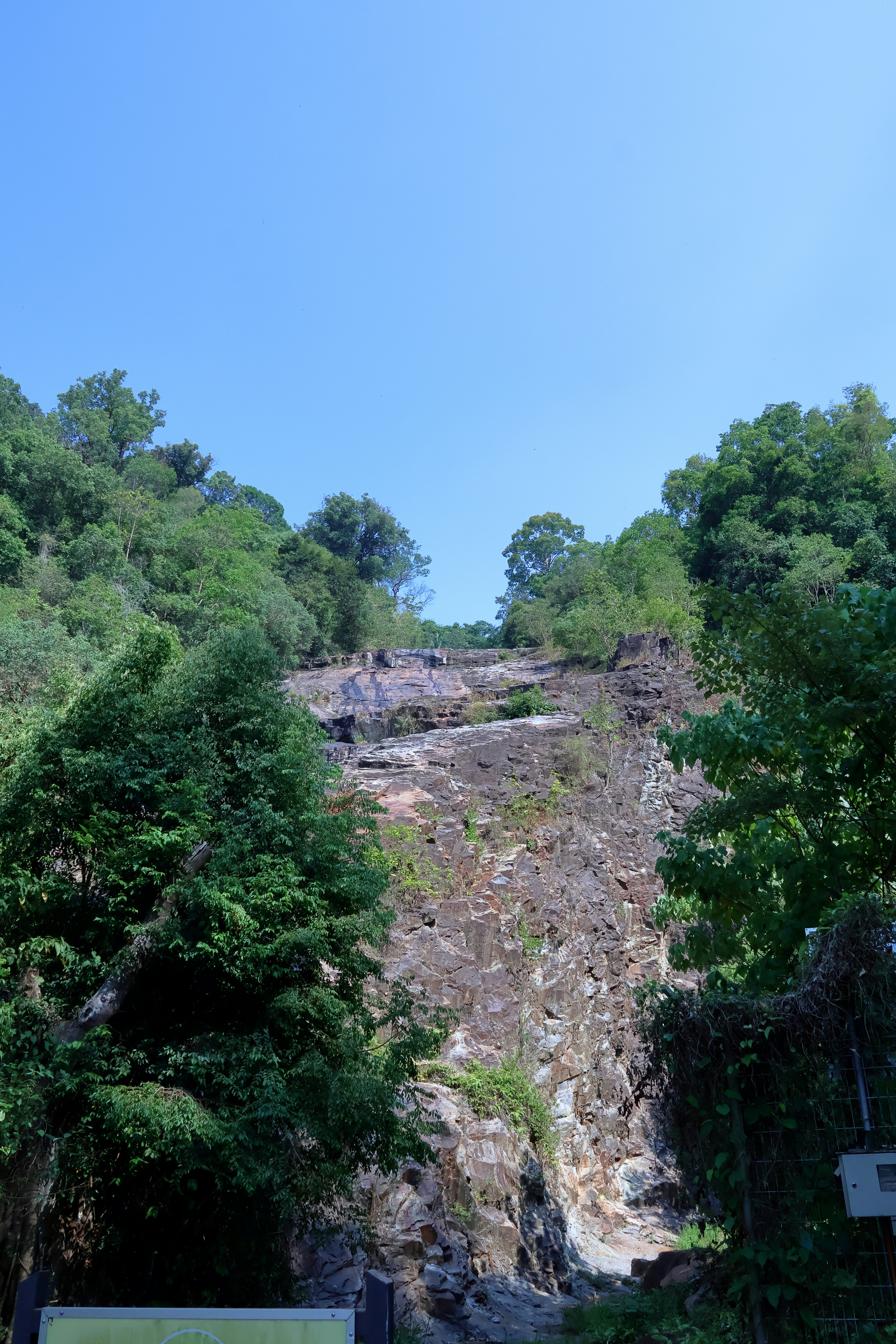 Vertical cliff cascade under a clear summer sky