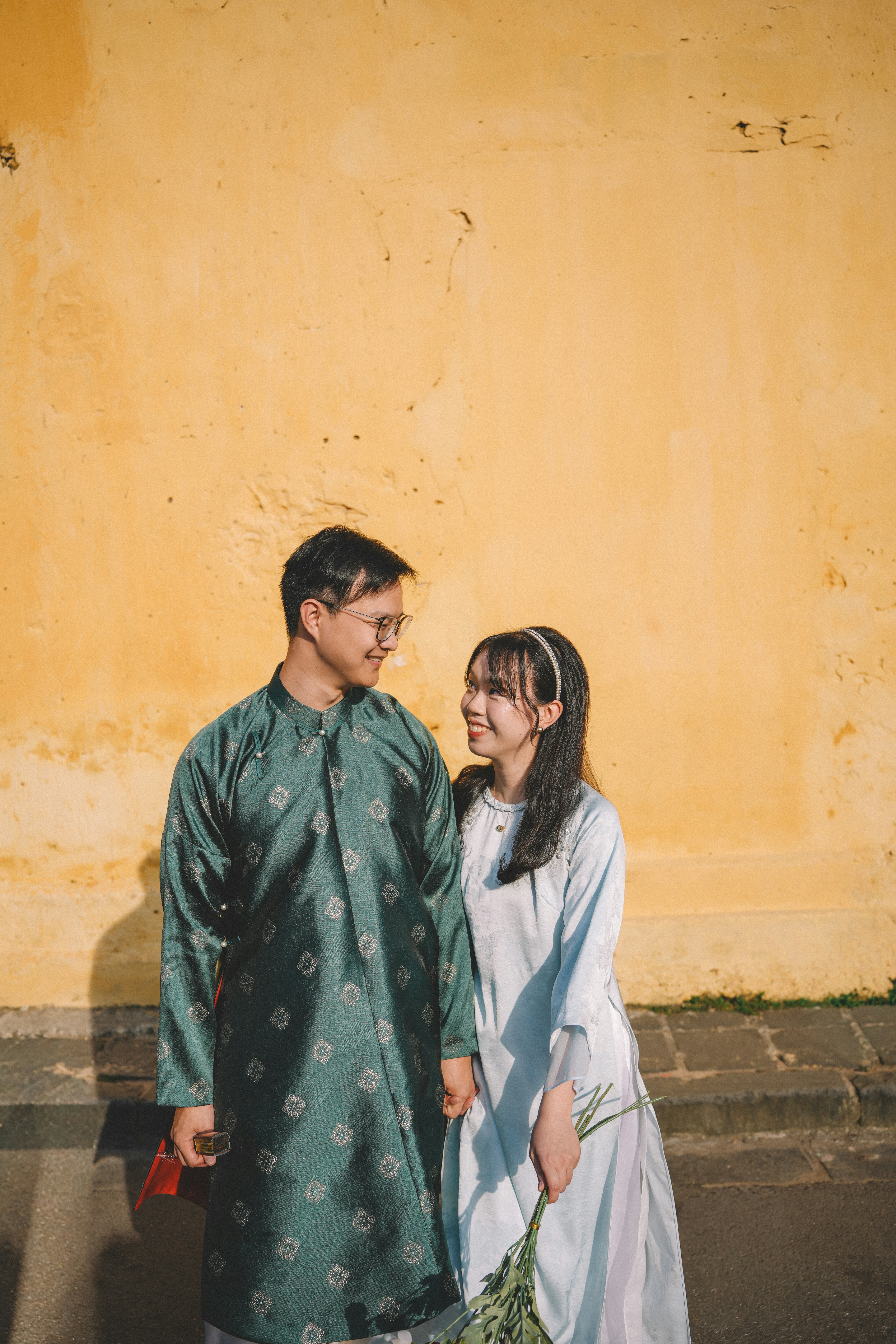 Couple in soft sunlight by a sunlit ochre wall