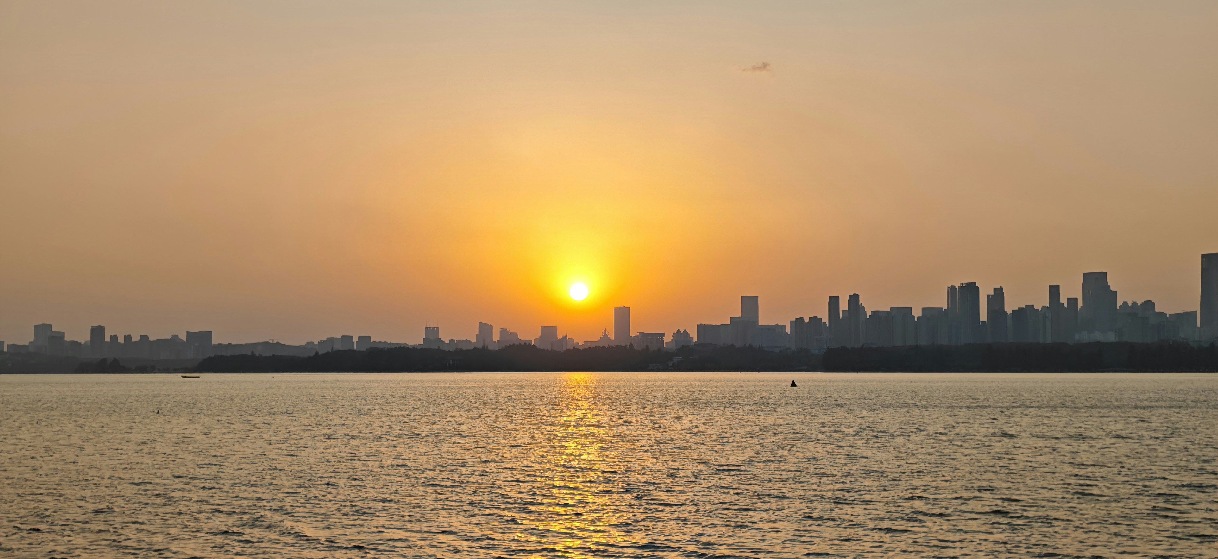 Sunlit Horizon: City Silhouette at Dusk over Quiet Waters