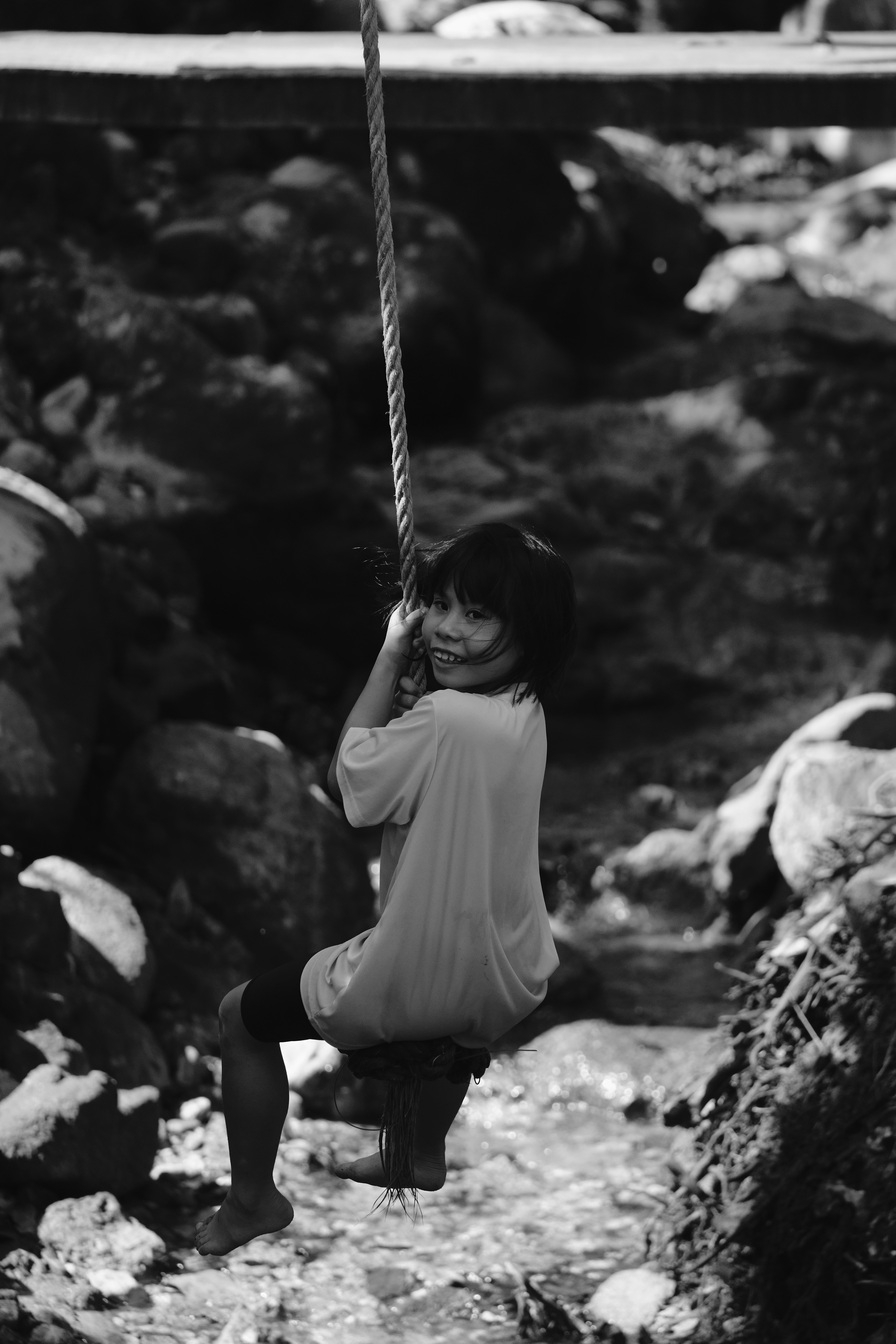 Child on a rope swing in a sunlit rocky creek