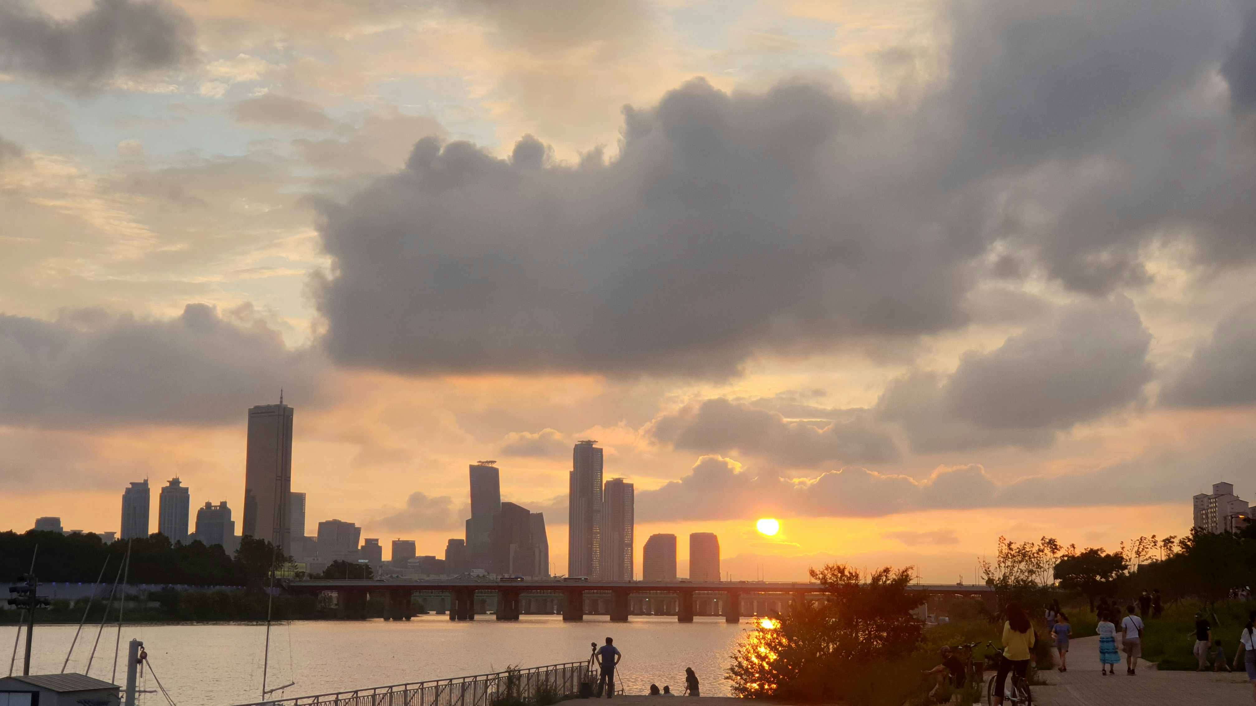 Sunset Skyline over the River with People by the Shore