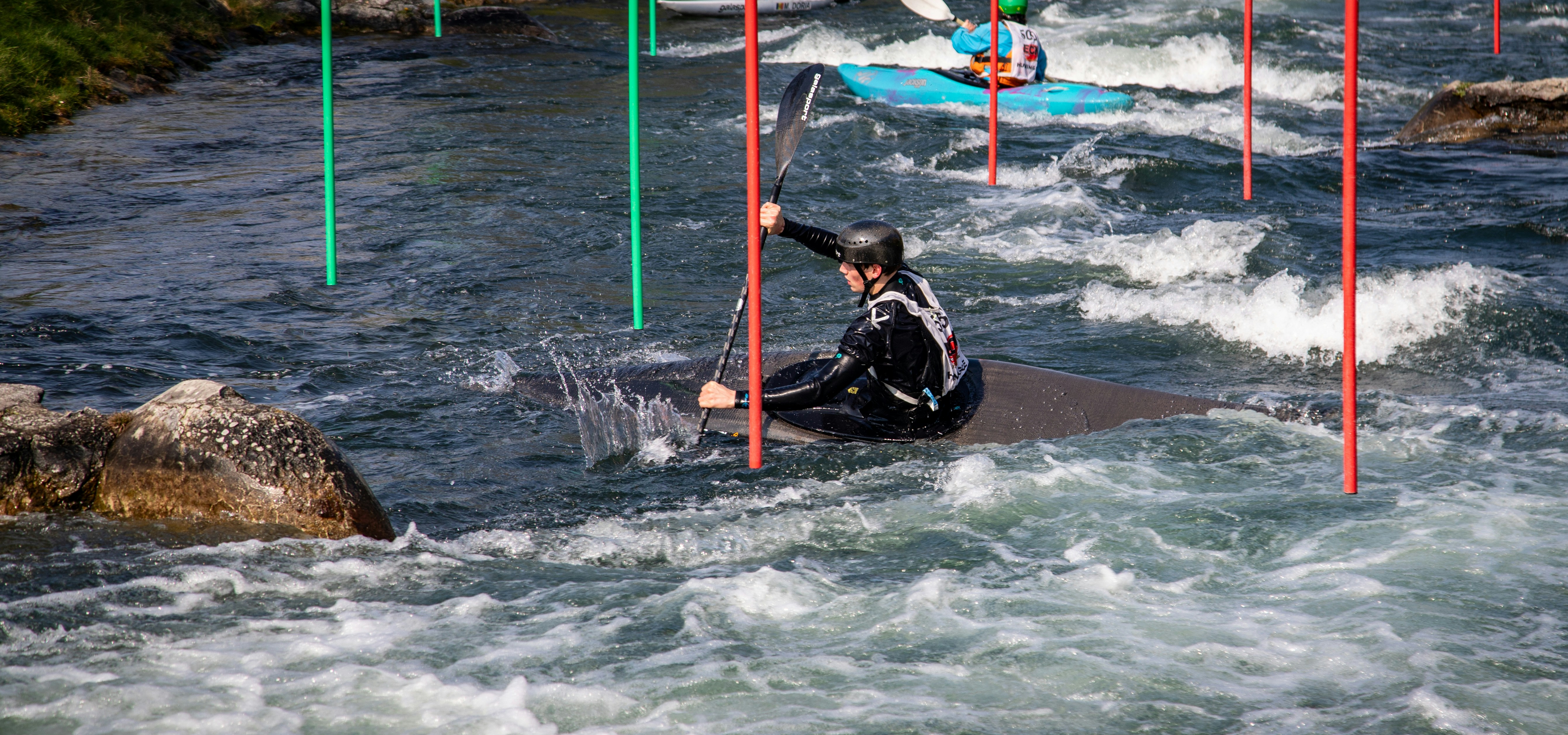 Racing the Rapids: Kayaker Navigates a Narrow Gate of Colorful Poles