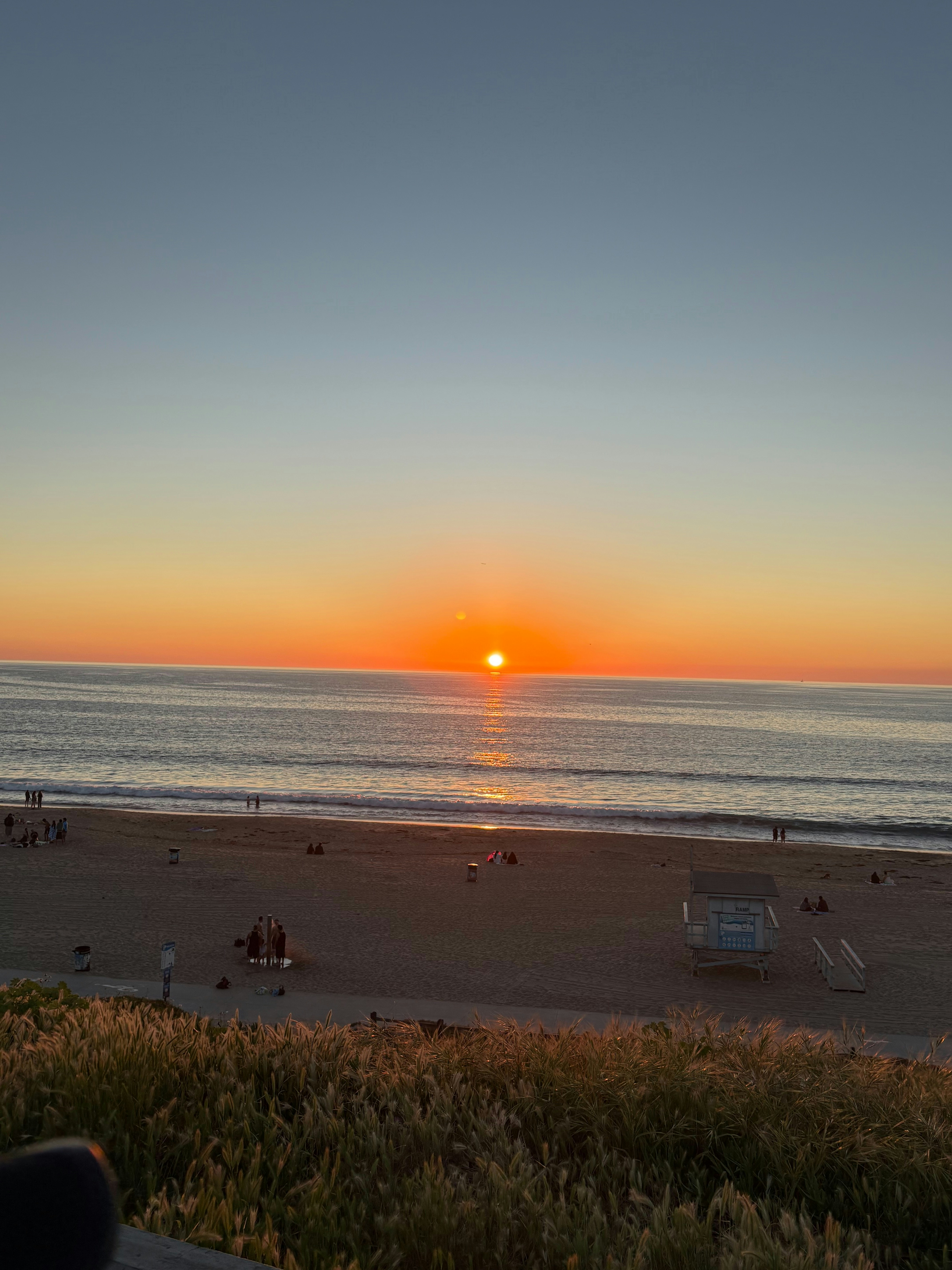 Sunlit Horizon: A Quiet Beach Sunset Over Gentle Waves