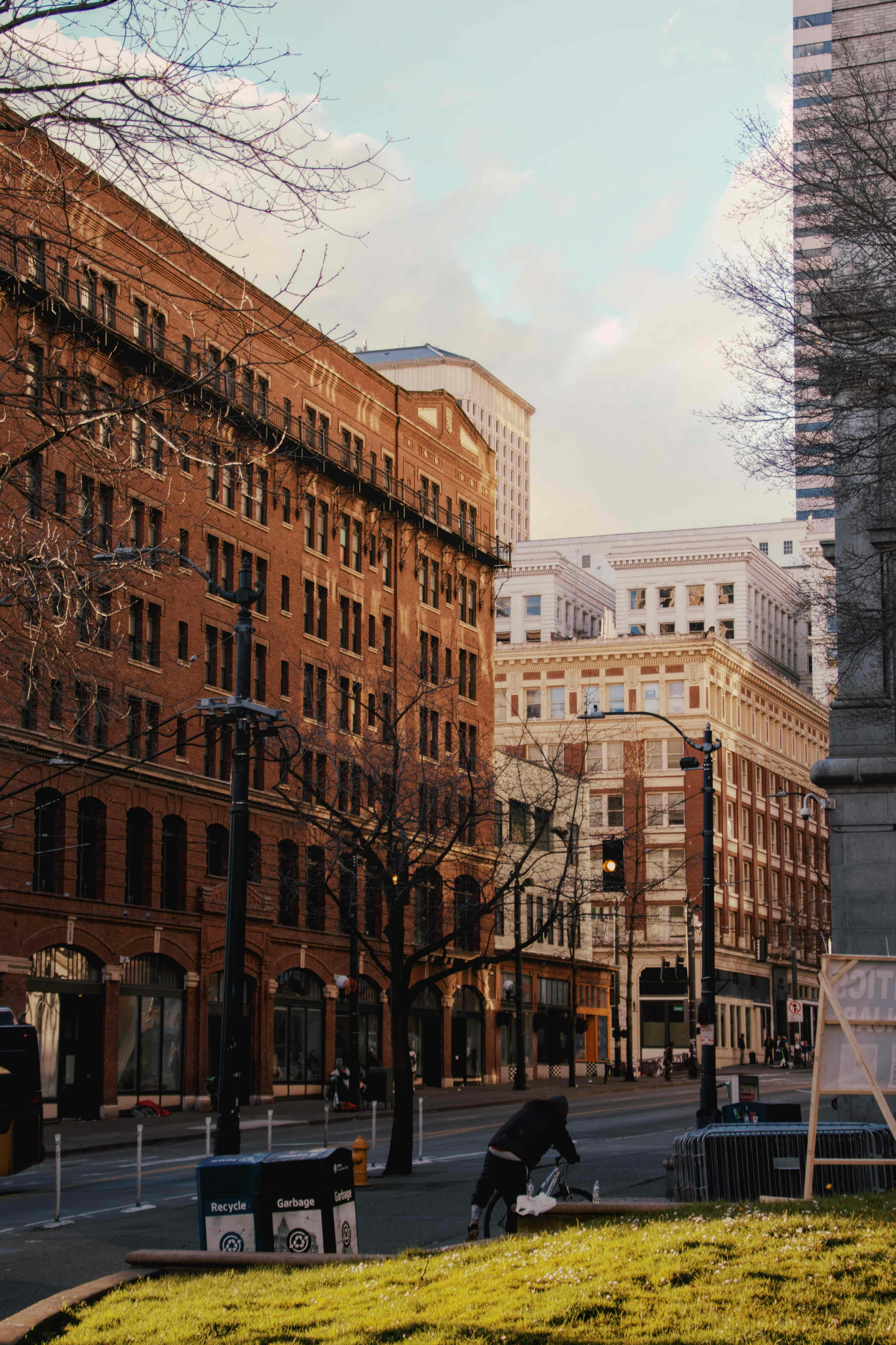 City Street in Golden Hour Light, A Bicycle Rider Near a Row of Brick Buildings