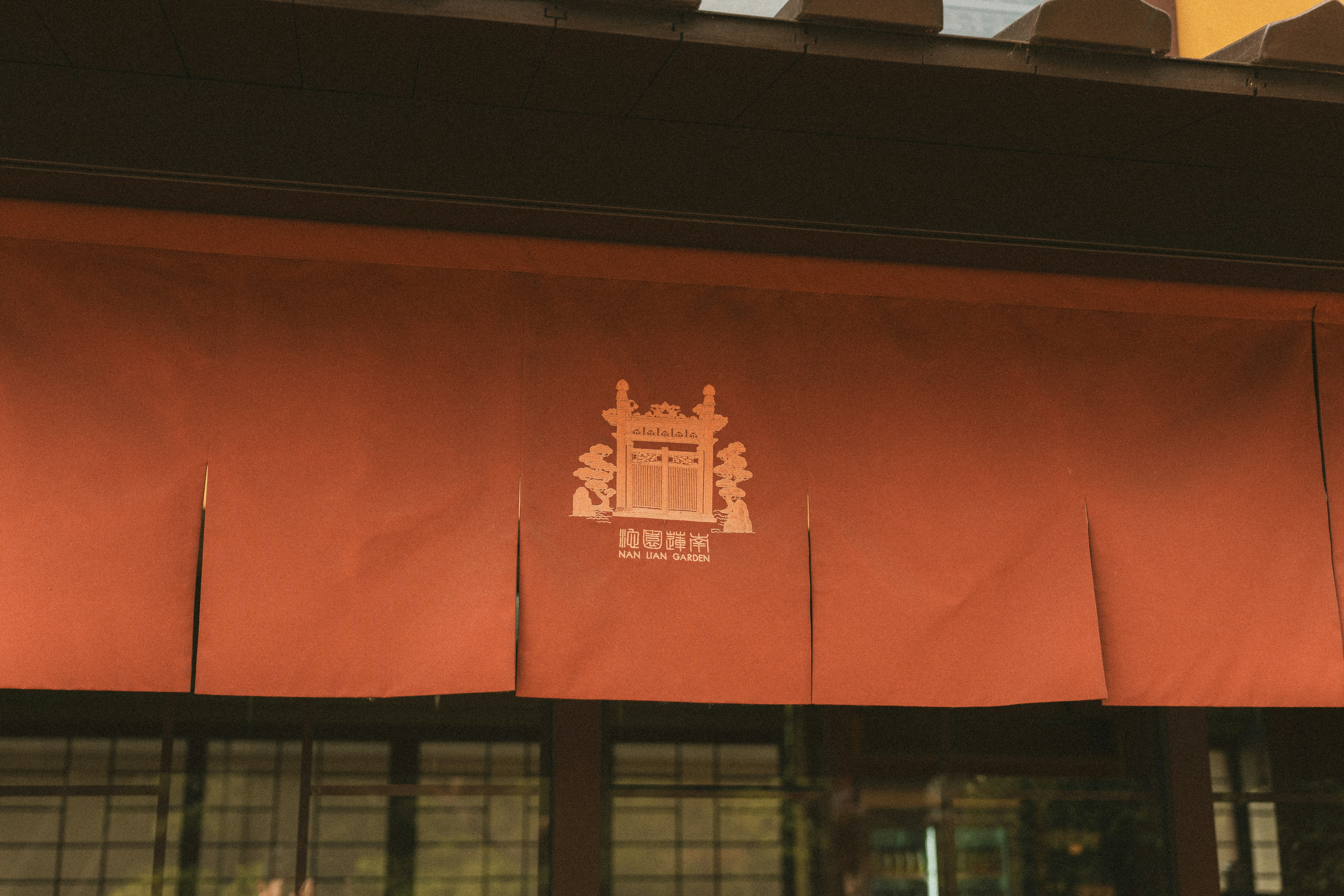 Gatecrest Hangout: A Red Curtain Reveals a Crest Above the Glass