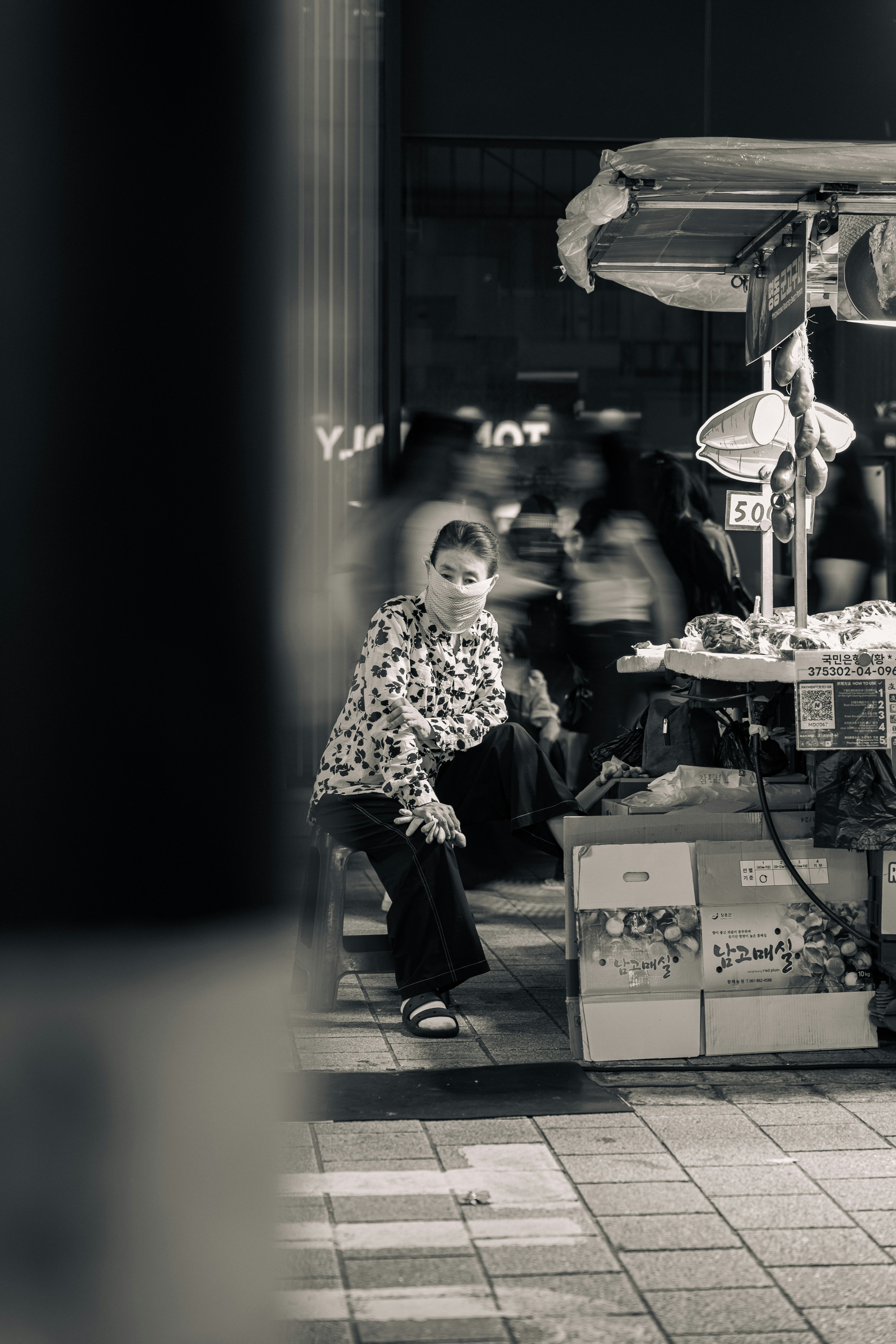 Masked Street Vendor: Quiet Contemplation Among Passing Faces