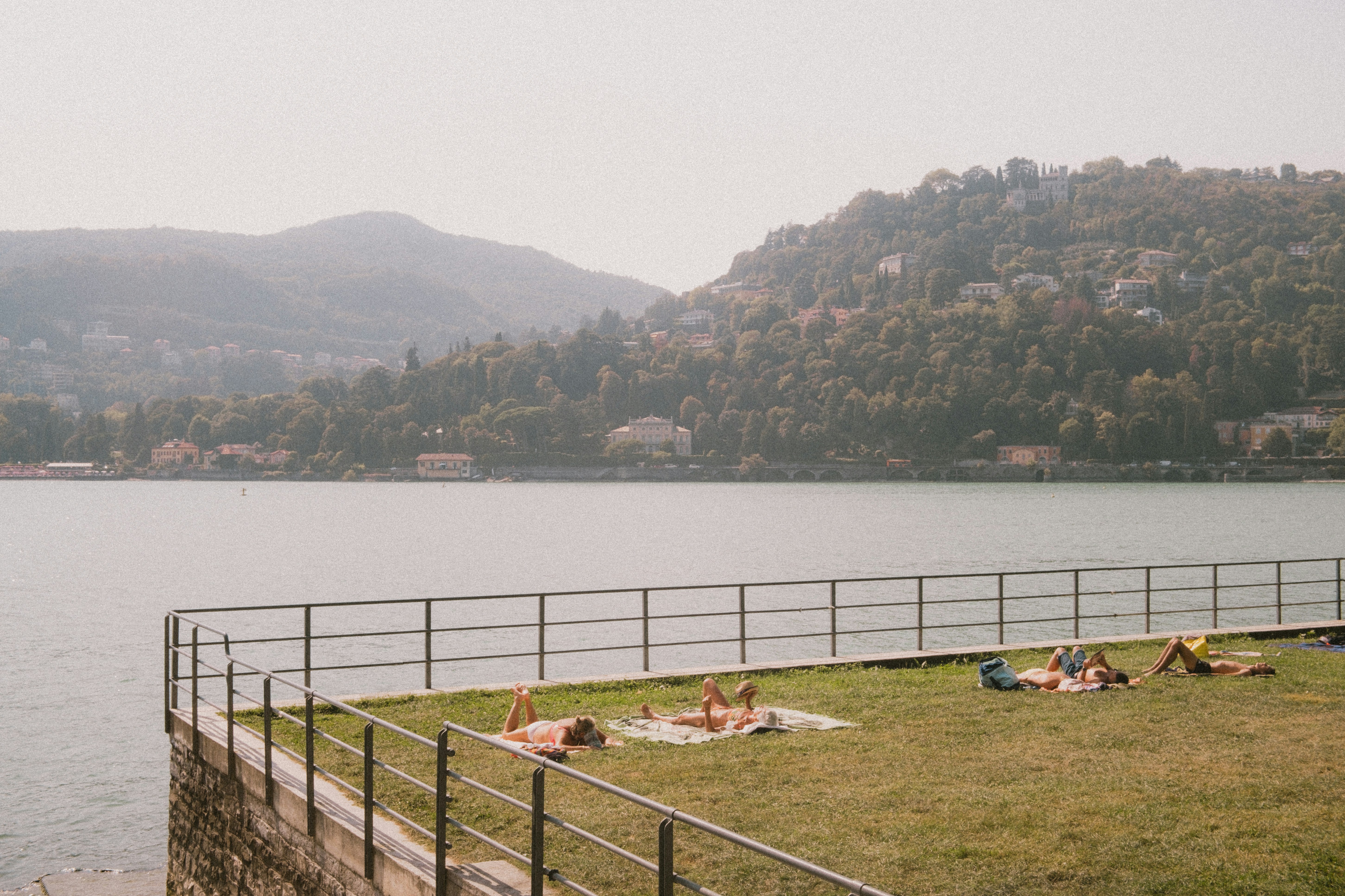 Sunlit lakeside lawn with distant hillside cottages