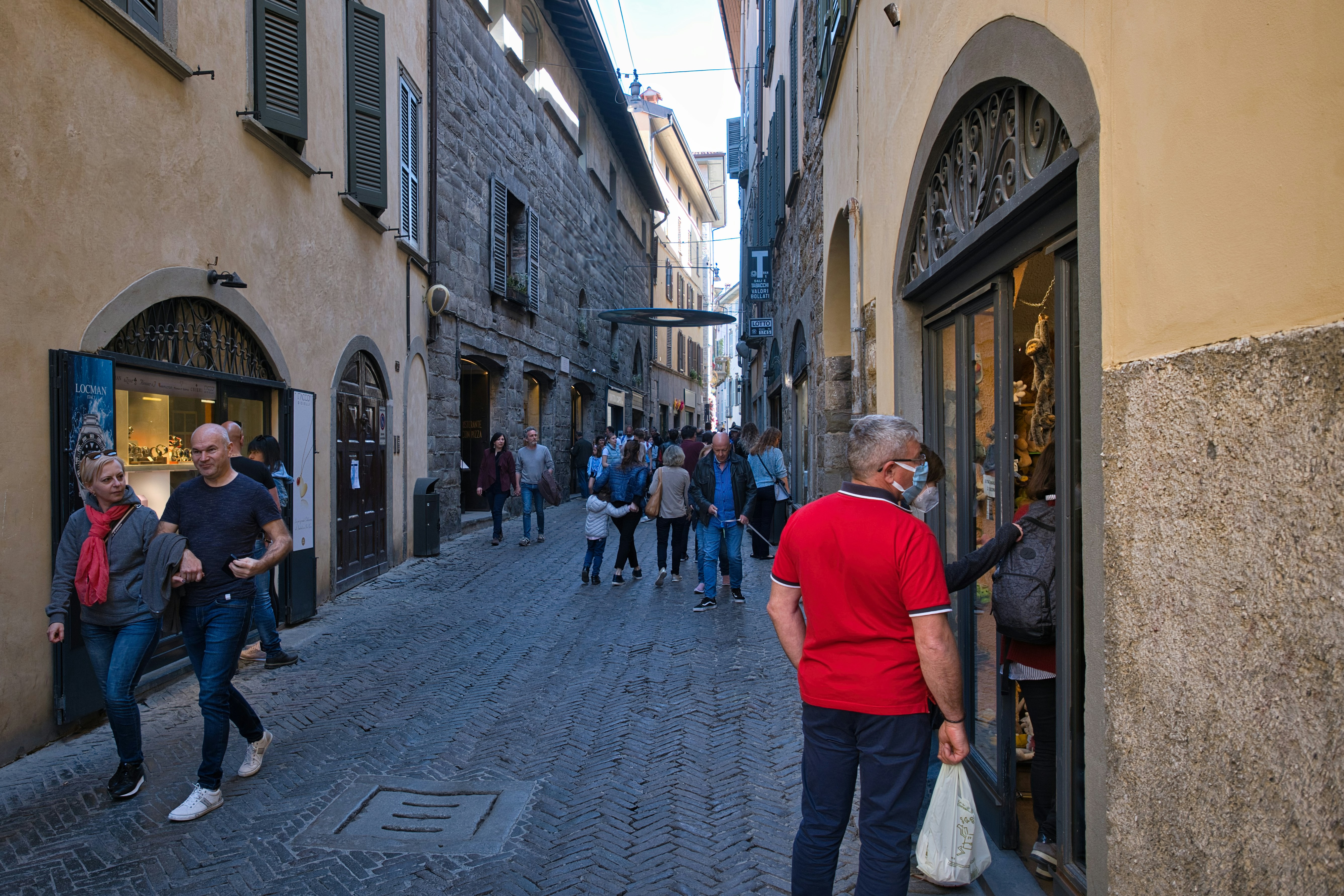 Busy cobblestone street in a sunlit European alleyway
