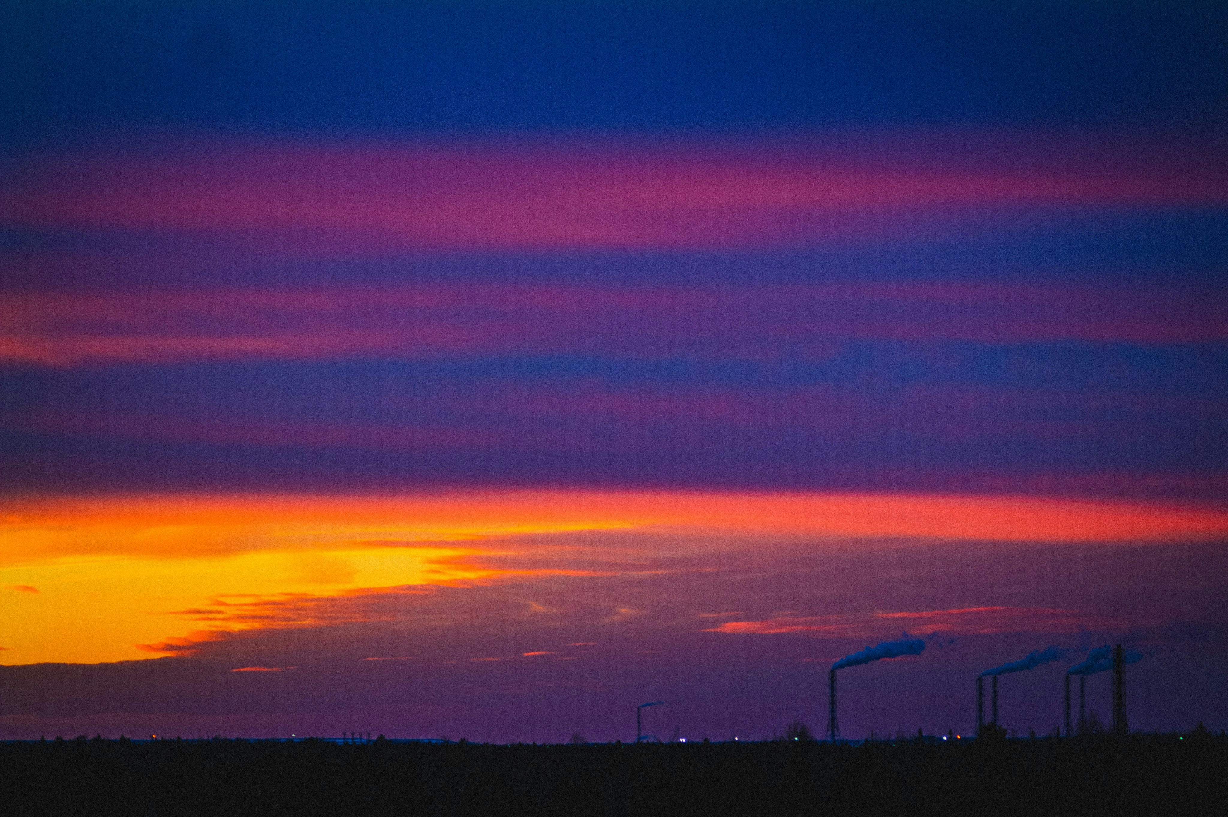 Dusk Over Industry: Slim Chimneys Crossing a Velvet Horizon