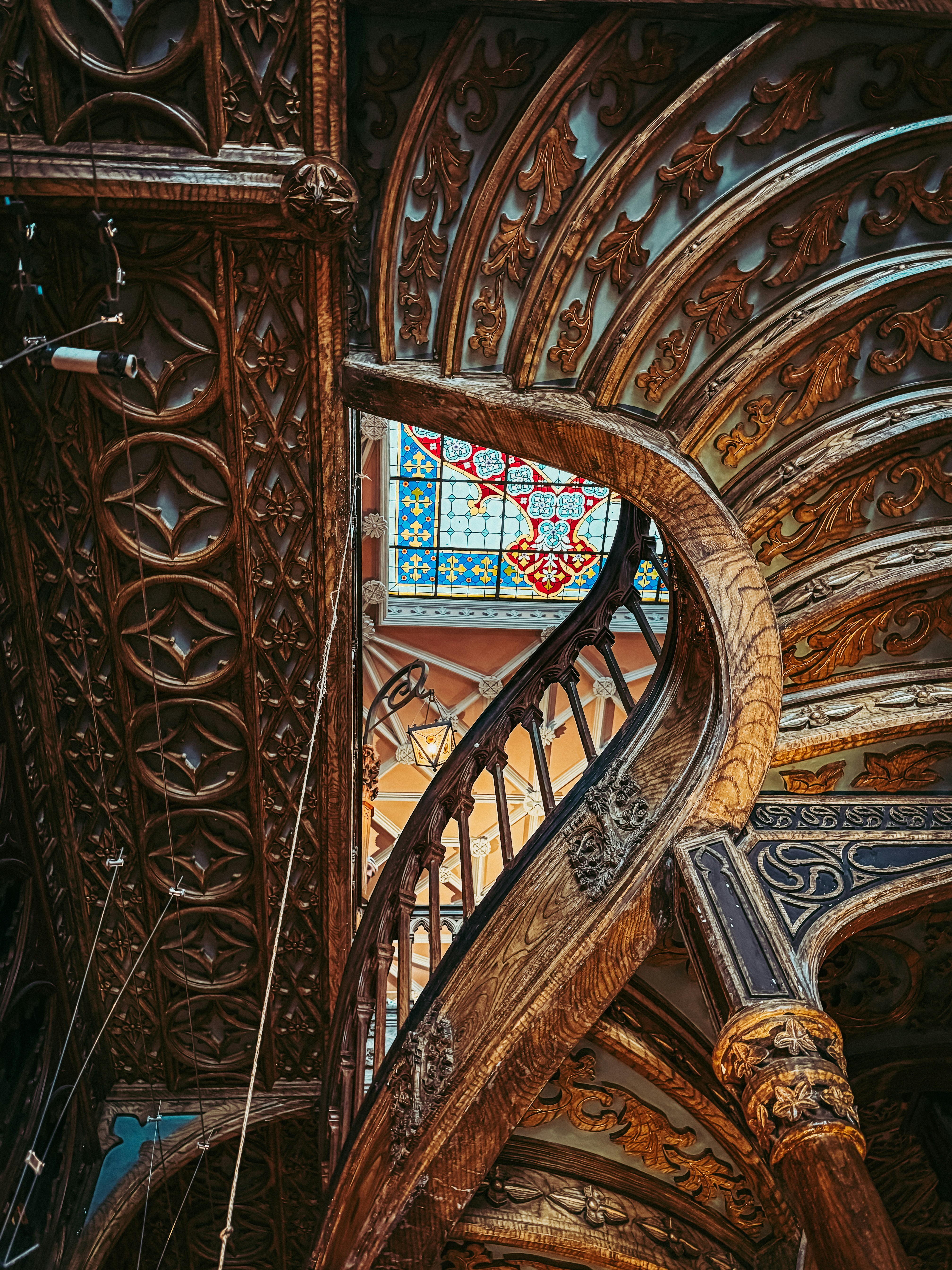 Ornate spiral staircase weaving through a stained-glass glow