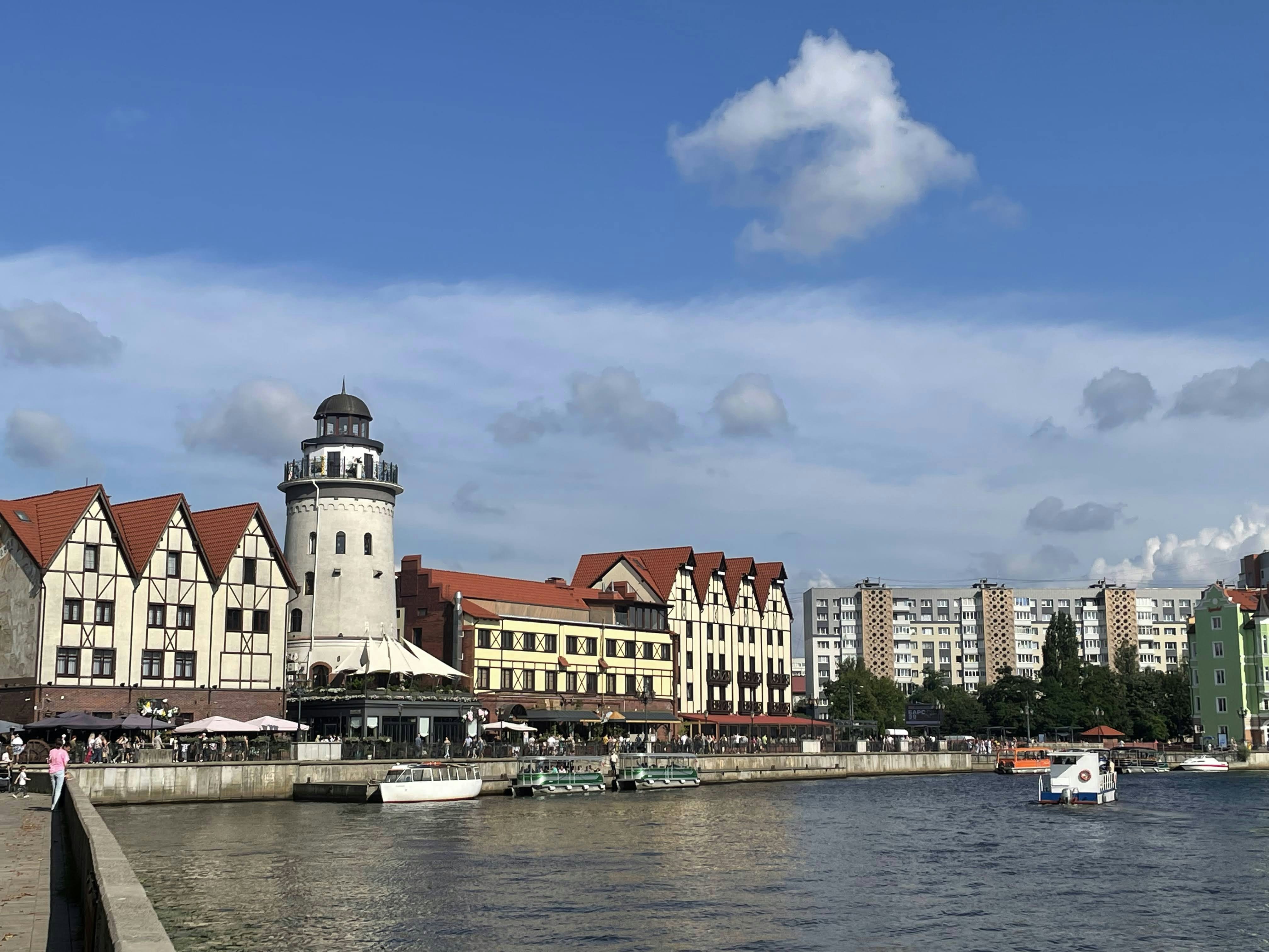 Lighthouse and waterfront row houses alongside calm harbor
