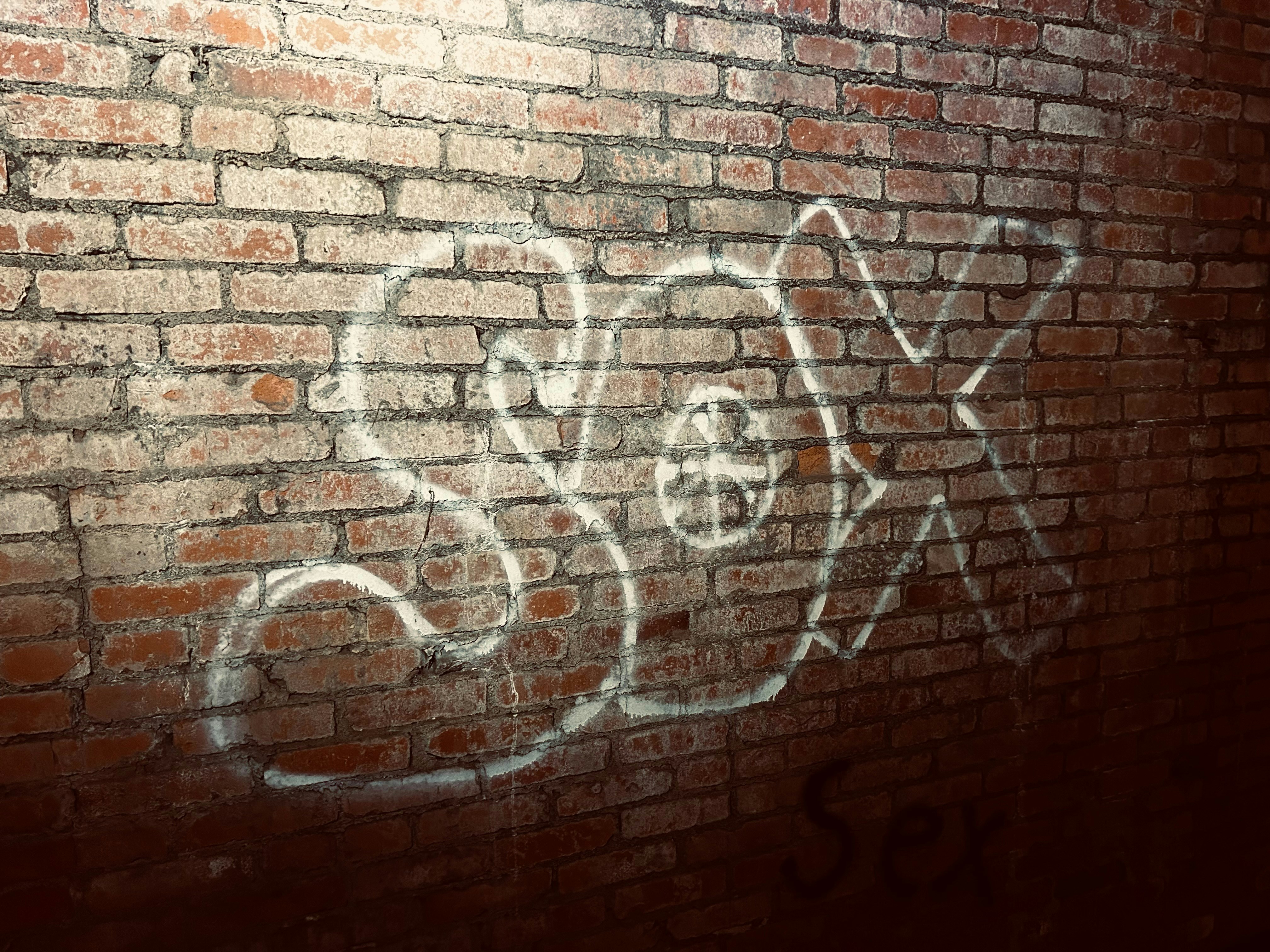 Chalked Graffiti on Brick Wall: A Quiet Spray of Letters and Shapes