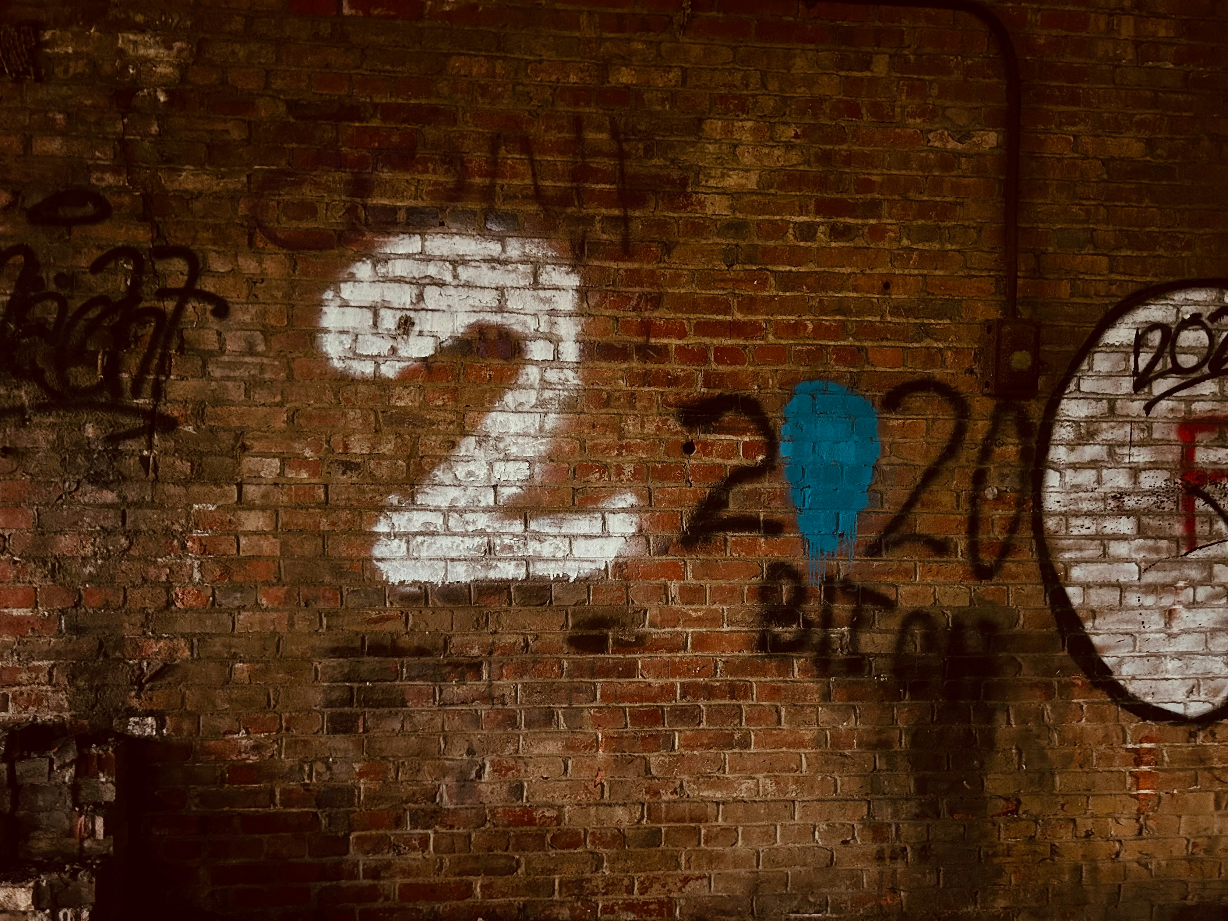 Brick Wall Glyphs: A White 2 and Blue Teardrop Graffiti Scene